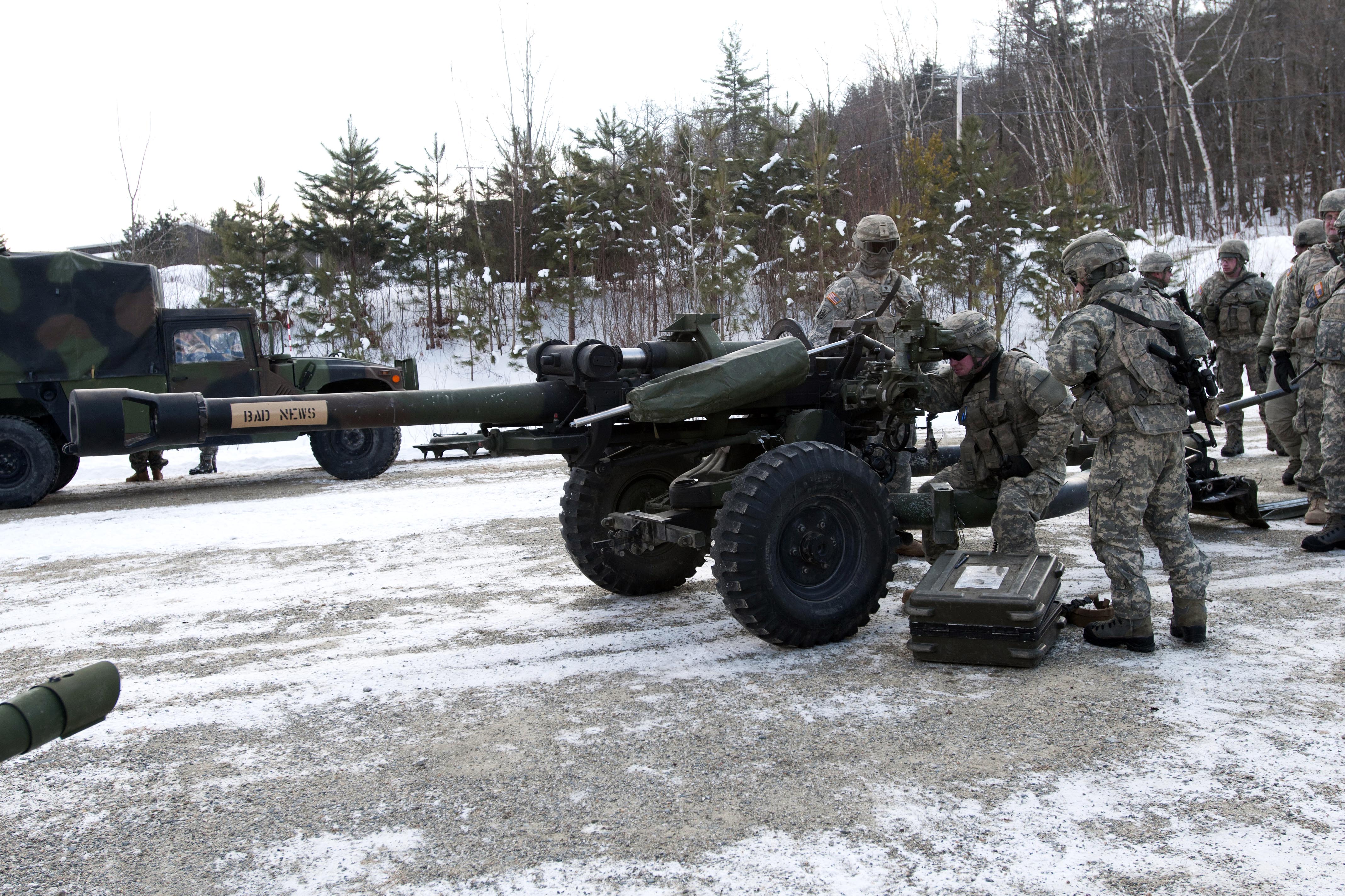 Army Sgt. Matthew Pratt, center, sights in on the M119 howitzer during ...