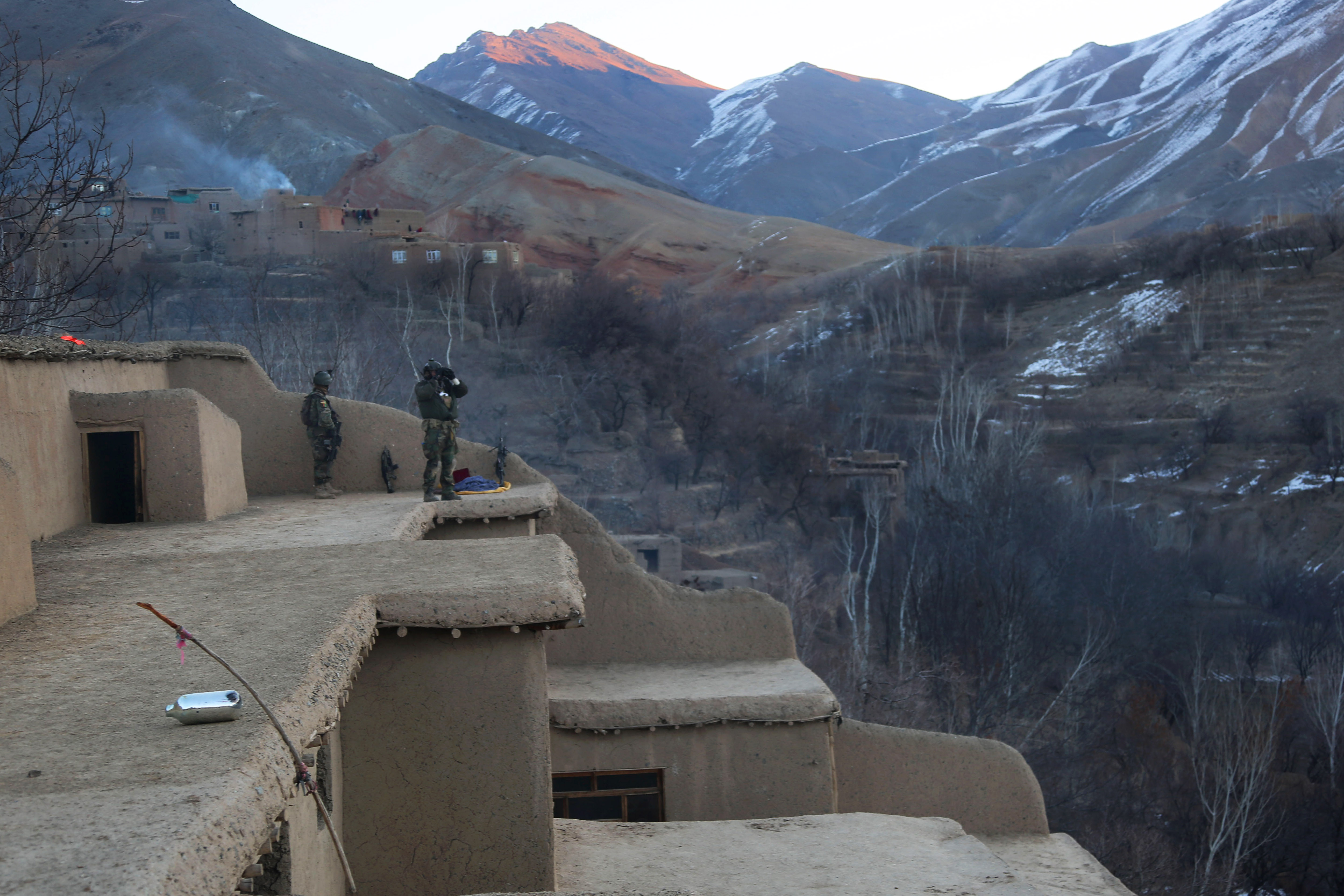 A U.S. Special Forces soldier uses binoculars to survey the valley for ...