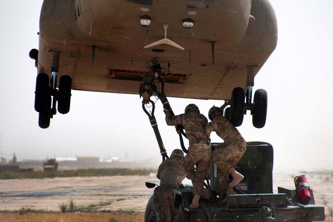 U.S. soldiers secure the cargo line to a CH-47 Chinook helicopter load ...