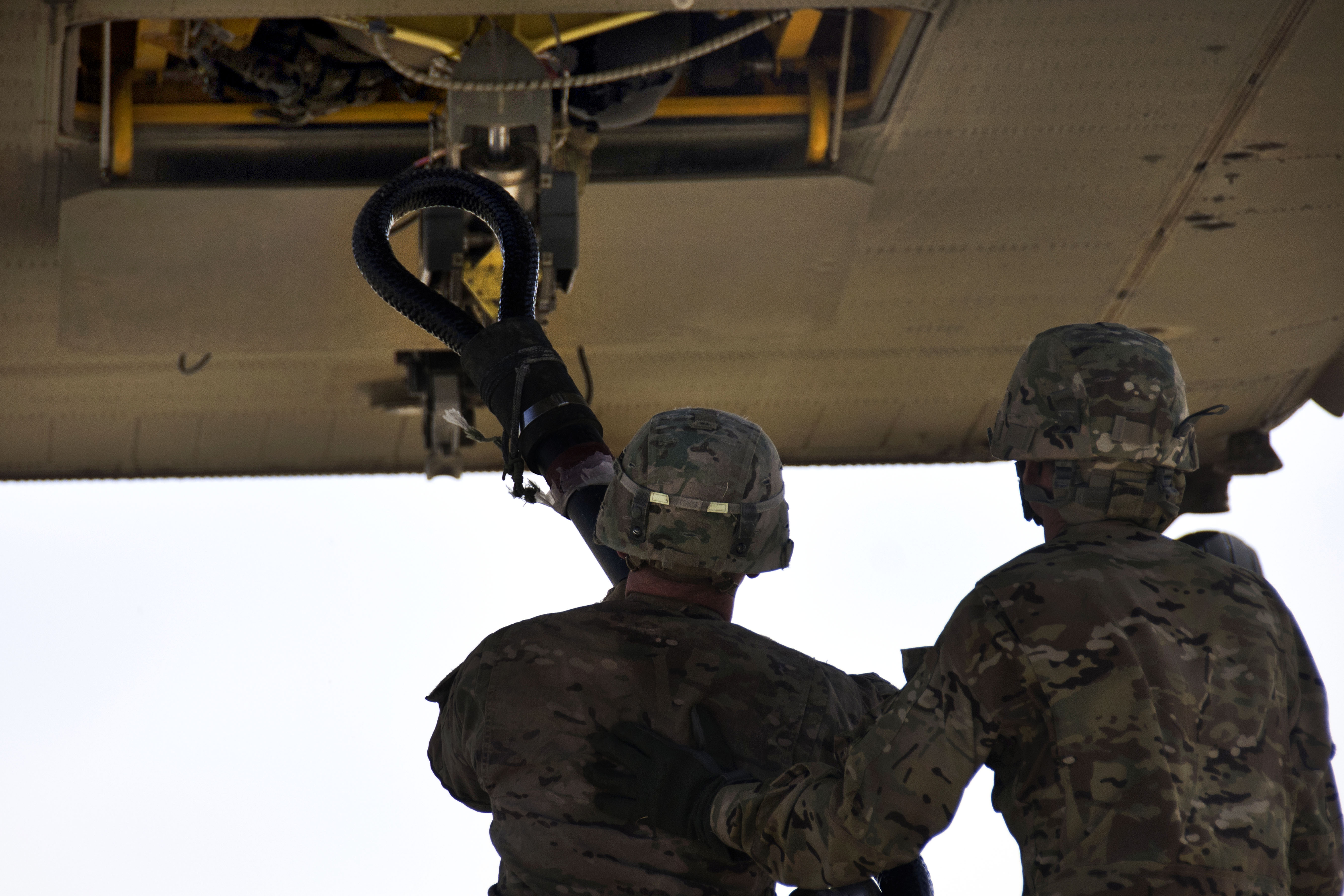 U.S. soldiers secure the cargo line to a CH-47 Chinook helicopter load ...