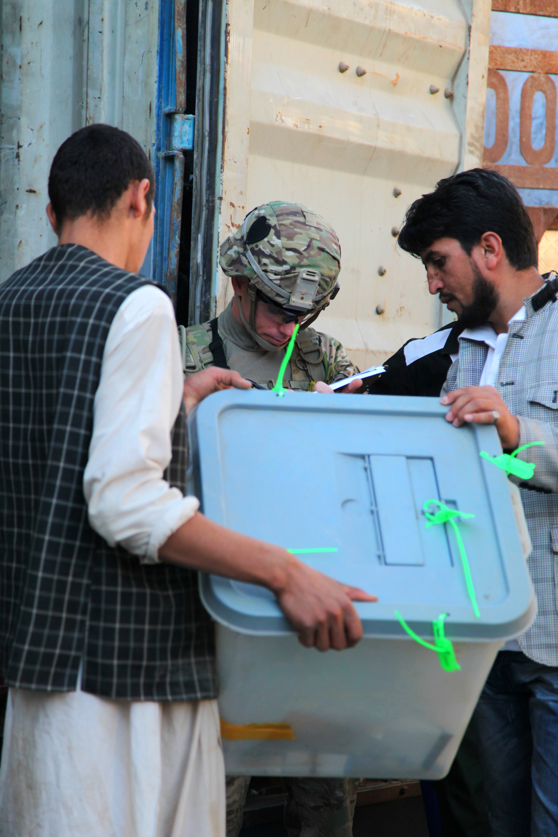Afghan workers handle ballot boxes while U.S. Maj. Landry, center ...