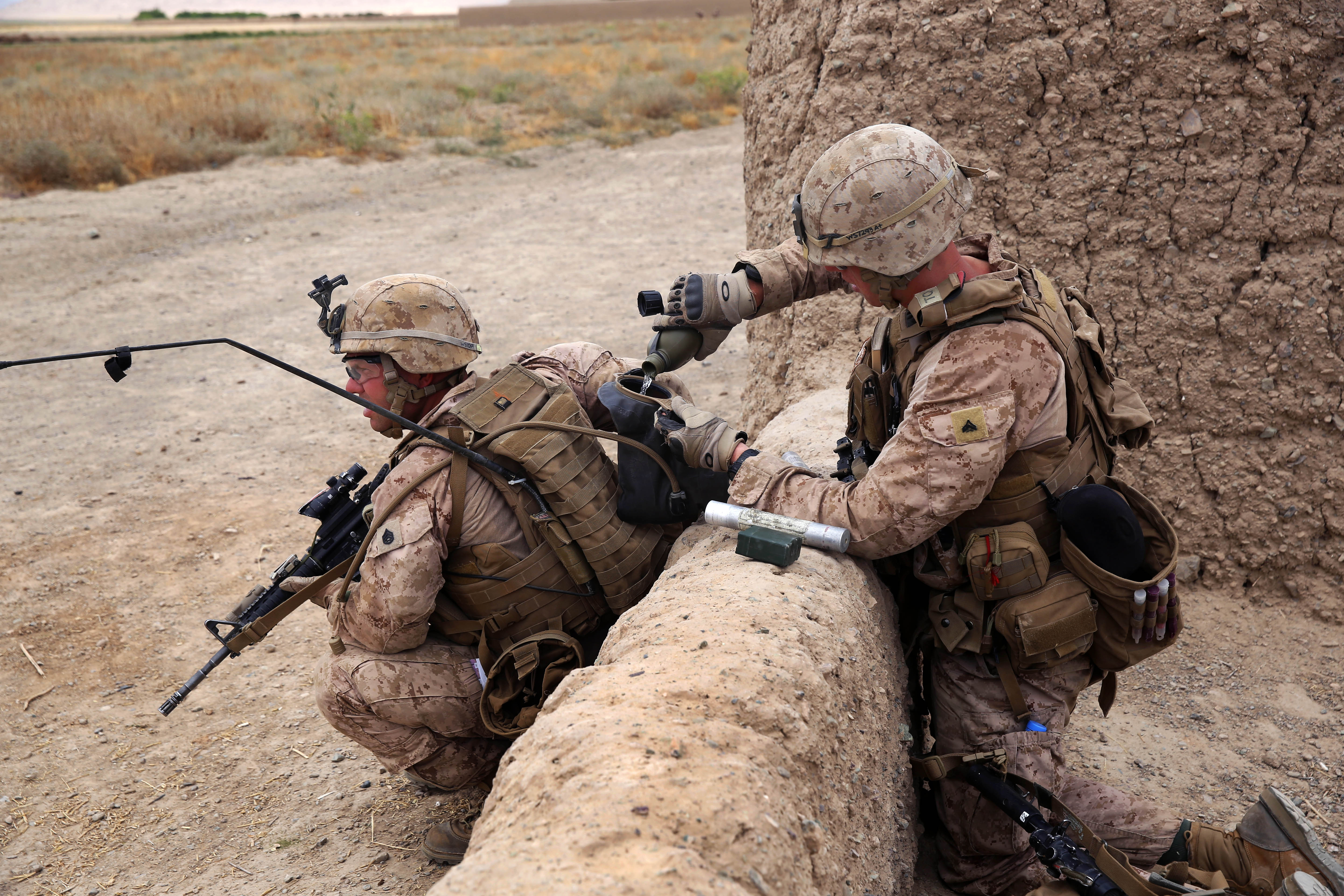 U.S. Marine Corps Cpl. Colin Schafer, right, fills a camelback bladder ...