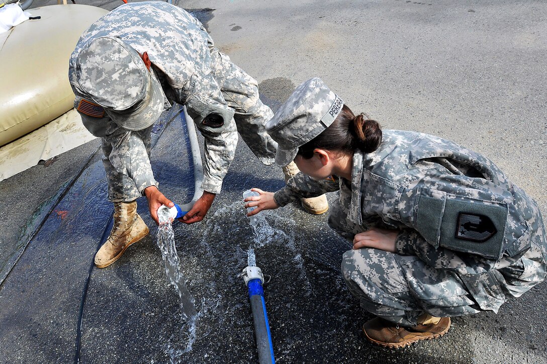 Army Spc. Pamela Pereira, right, collects a water sample during ...