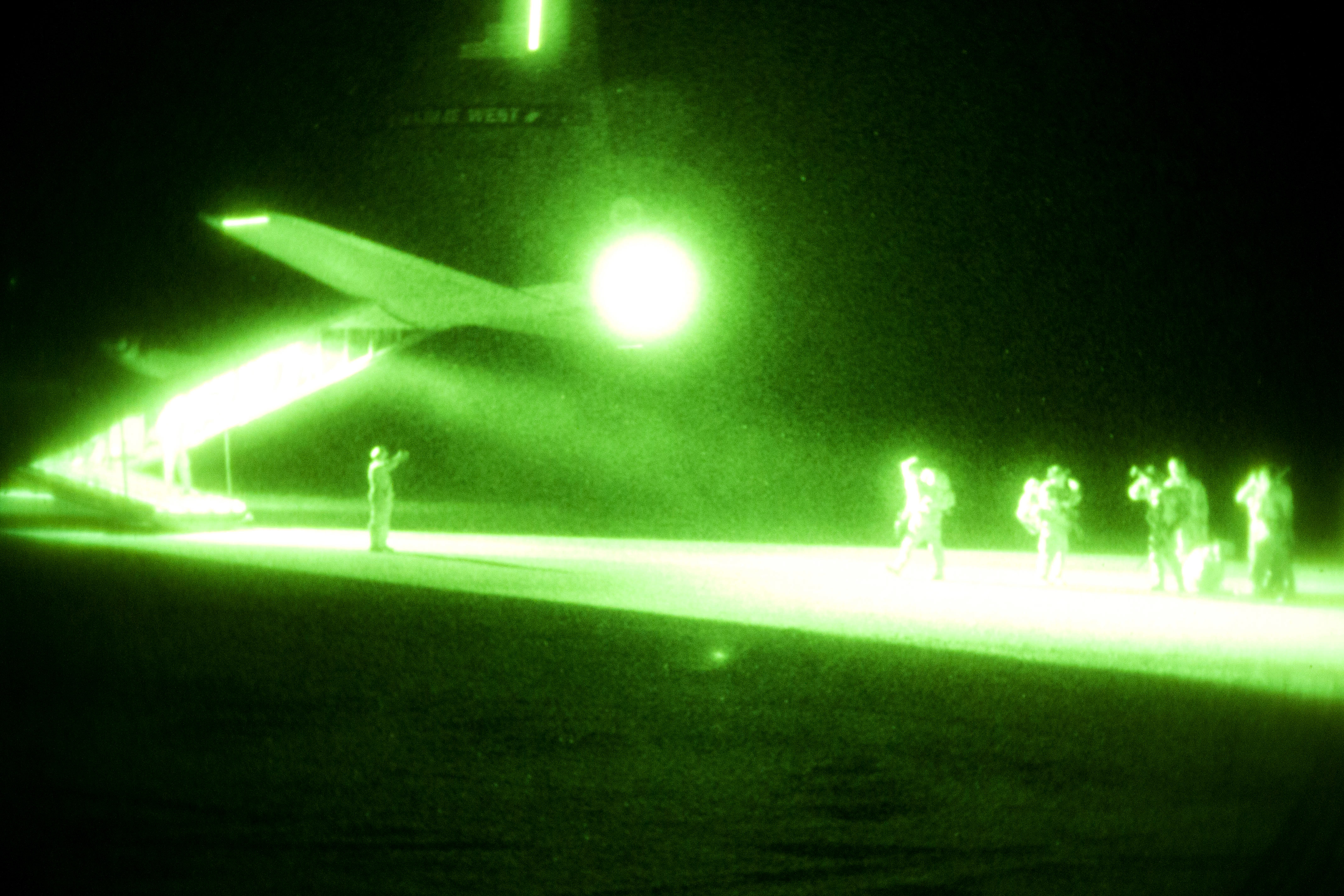 As seen through a night-vision device, U.S. Air Force airmen board a C ...