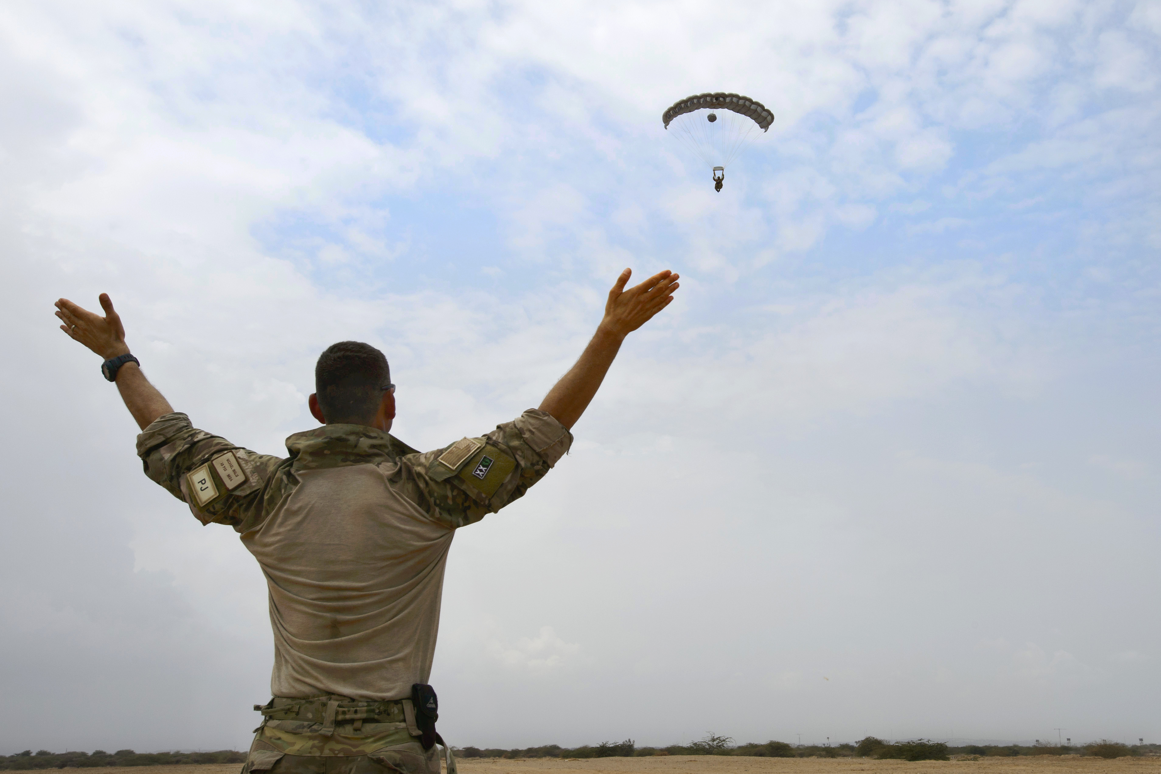 A U.S. Air Force pararescueman signals to jumpers during free fall jump ...