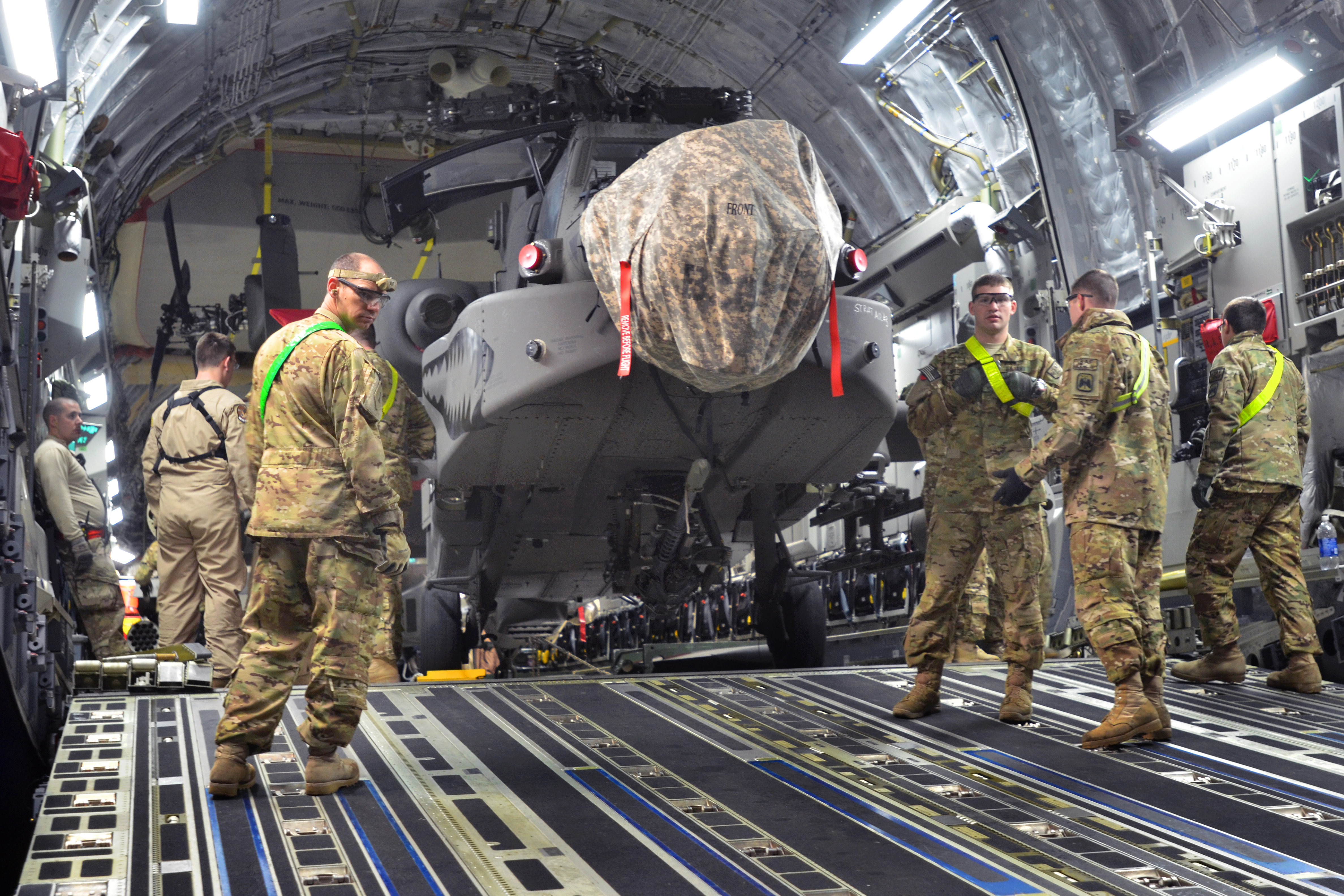 U.S. soldiers and airmen unload an AH-64E Apache Guardian helicopter as ...