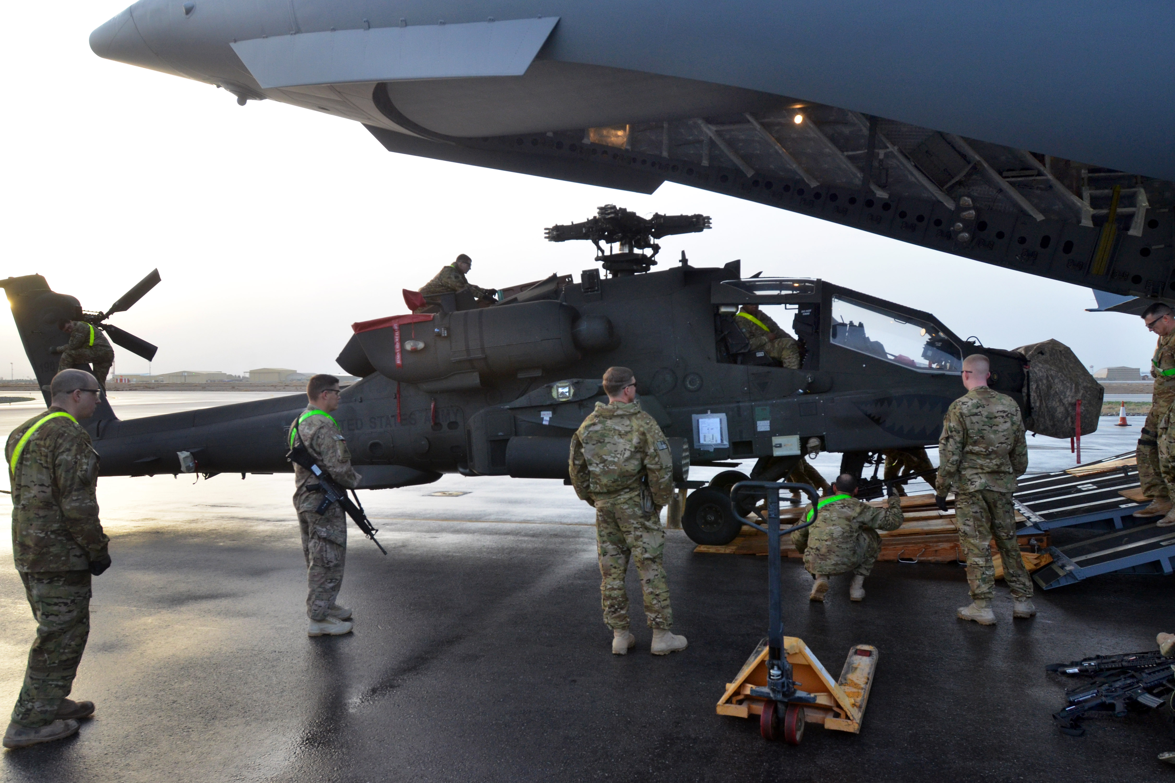 The sun rises off the tail of an AH-64E Apache Guardian helicopter as U ...