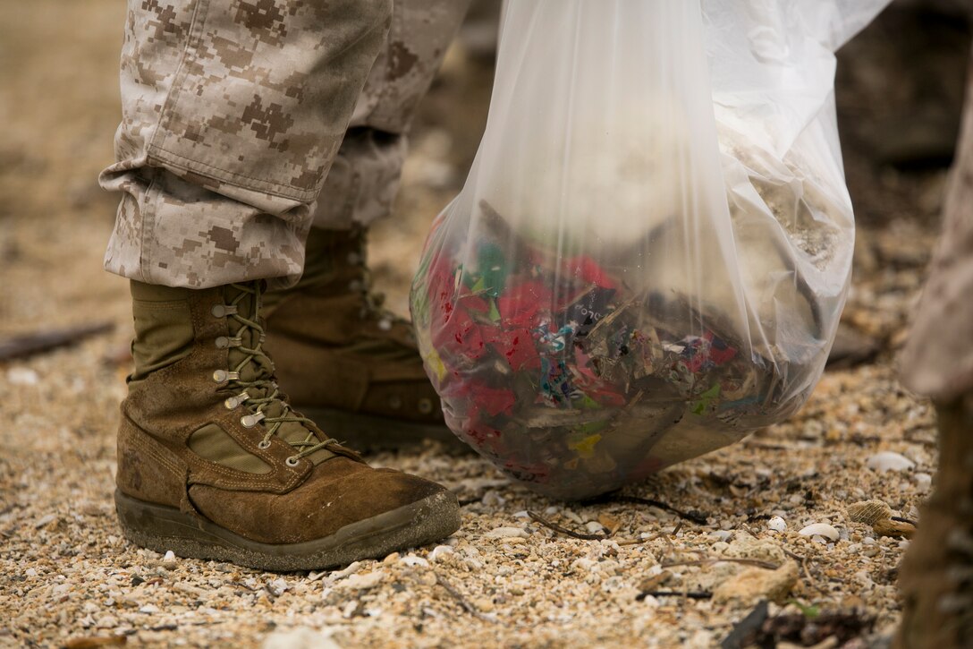 Marines sift through sand to pick up trash