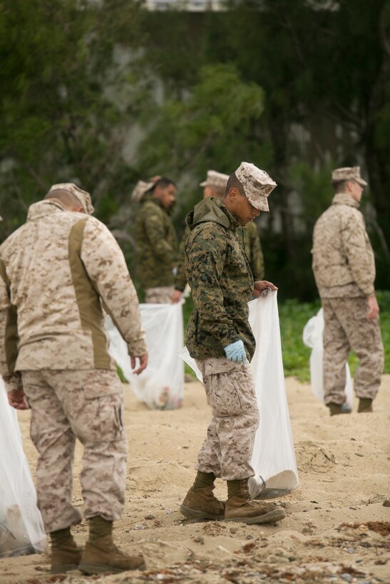 Marines sift through sand to pick up trash