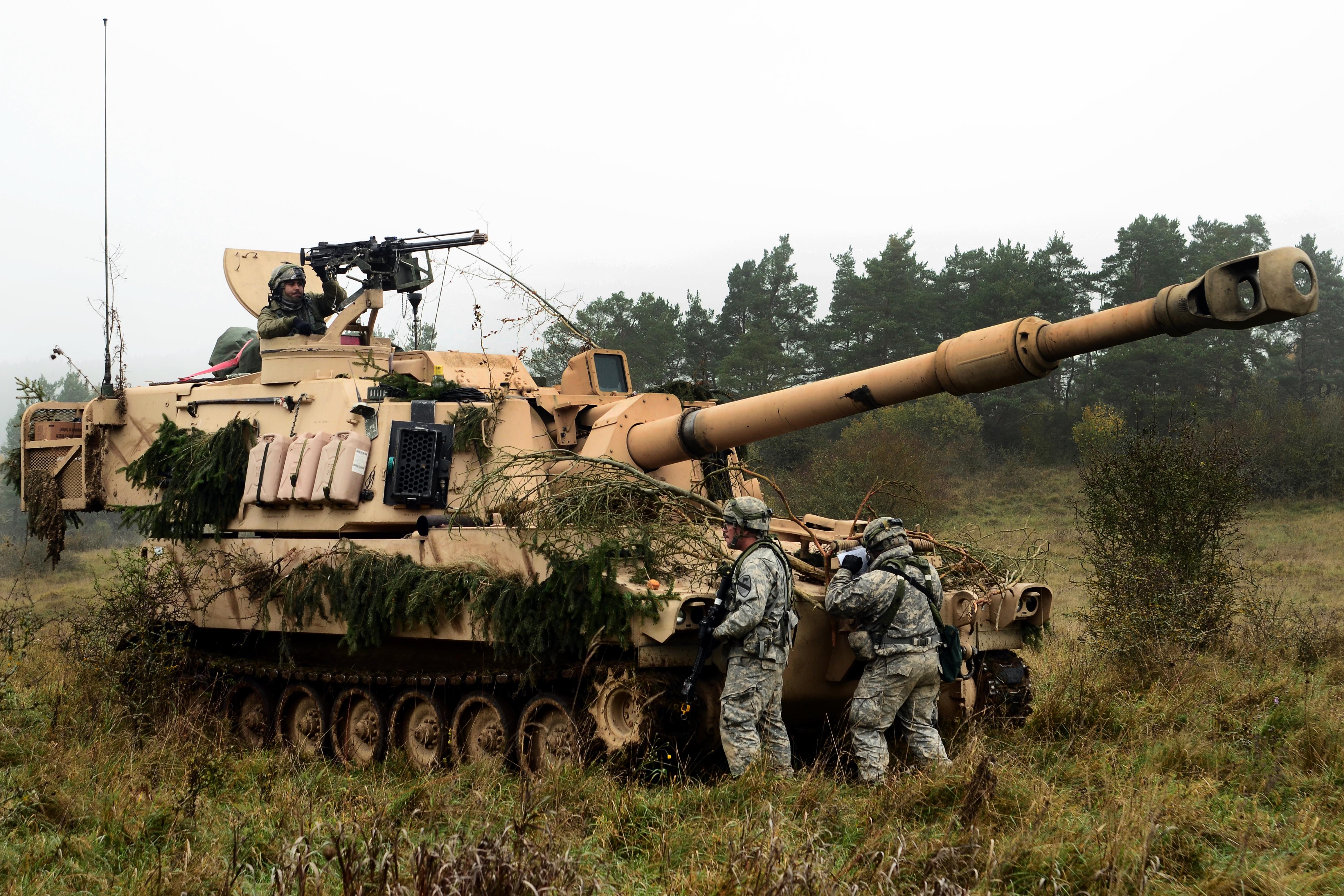 U.S. soldiers check the perimeter of an M109A6 Paladin howitzer during ...