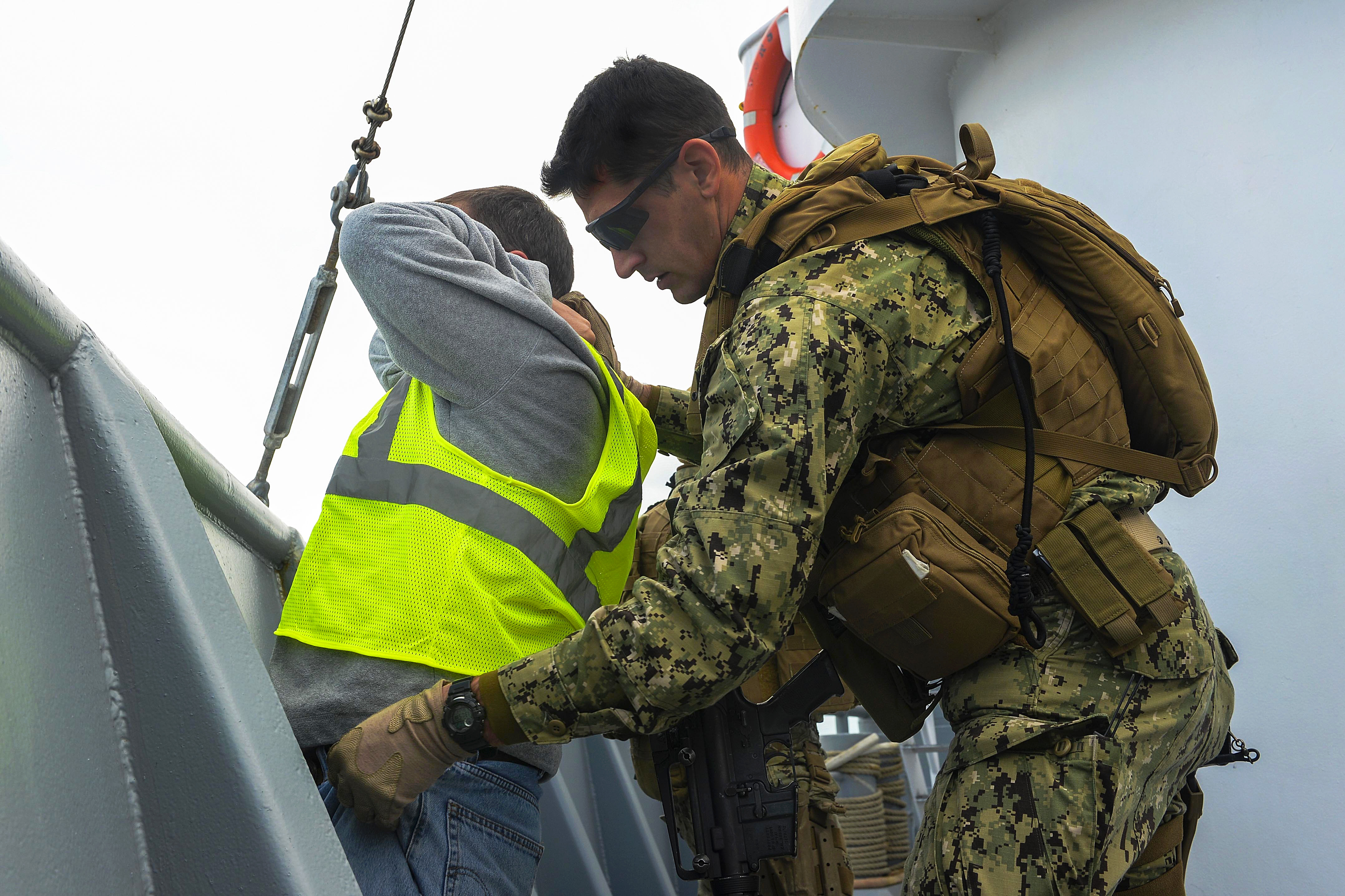 Navy Lt. j.g. Kristopher Devisser, right, searches a crew member of the ...