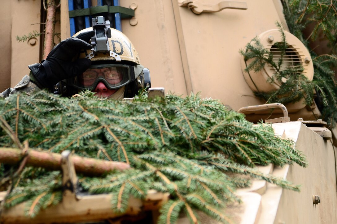 A U.S. soldier adjusts his helmet while driving an M109A6 Paladin ...