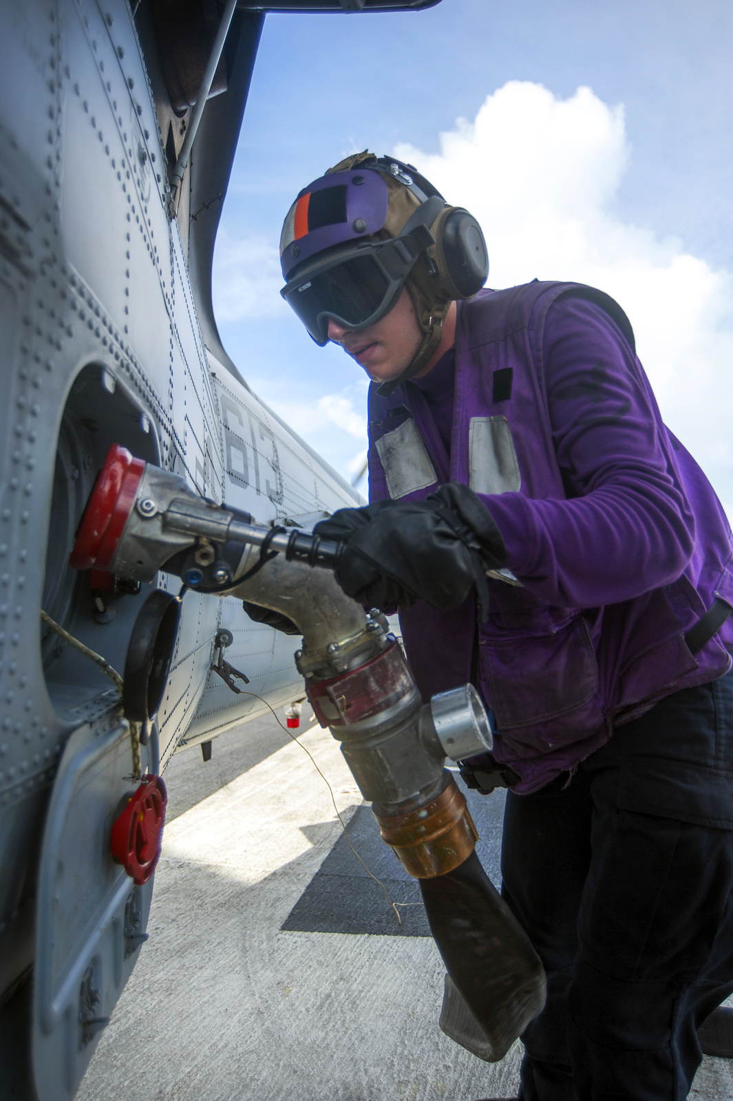U.S. Navy Petty Officer 3rd Class Matthew Overholt connects a fuel hose ...