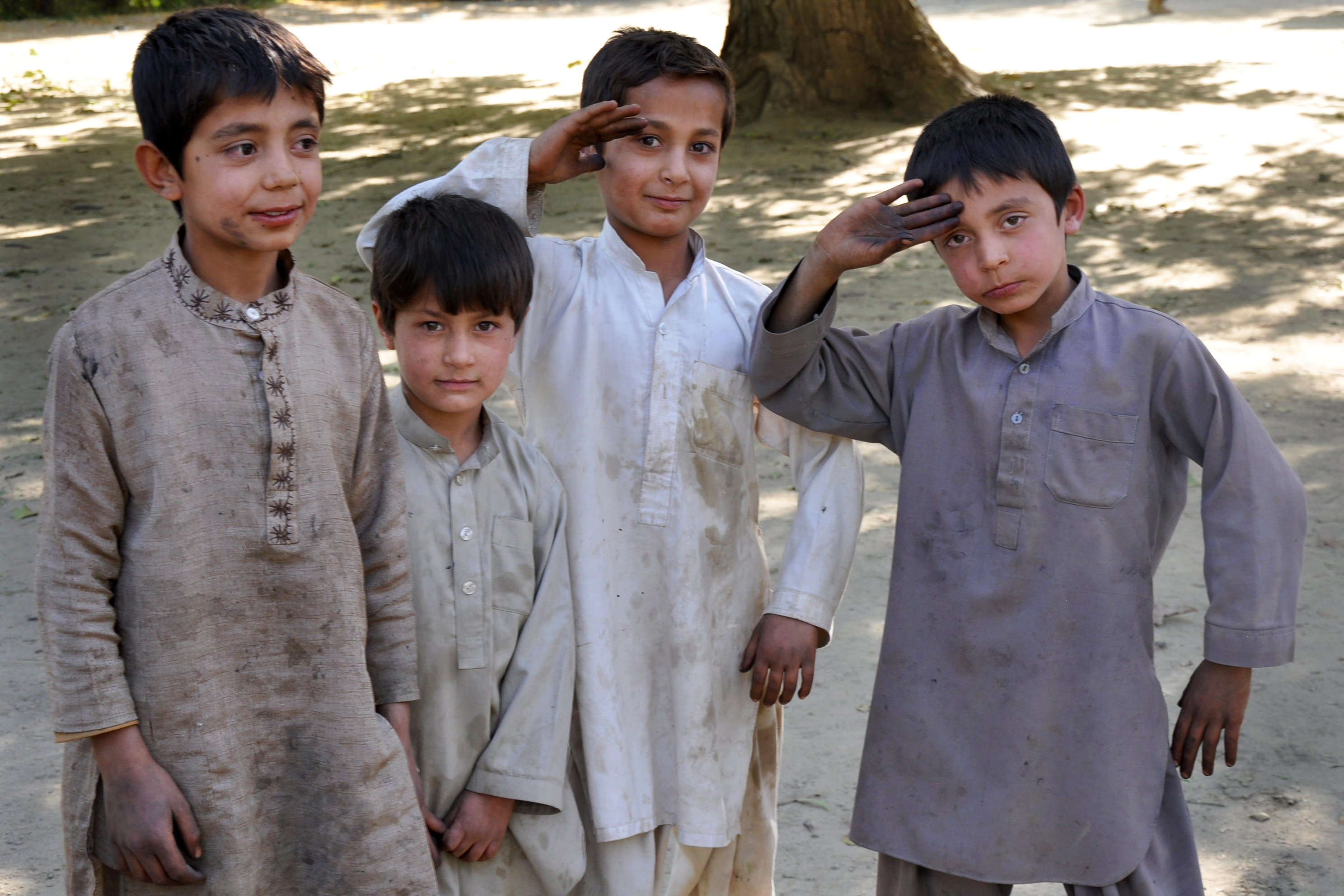 Afghan children watch and salute U.S. soldiers during a site visit to ...