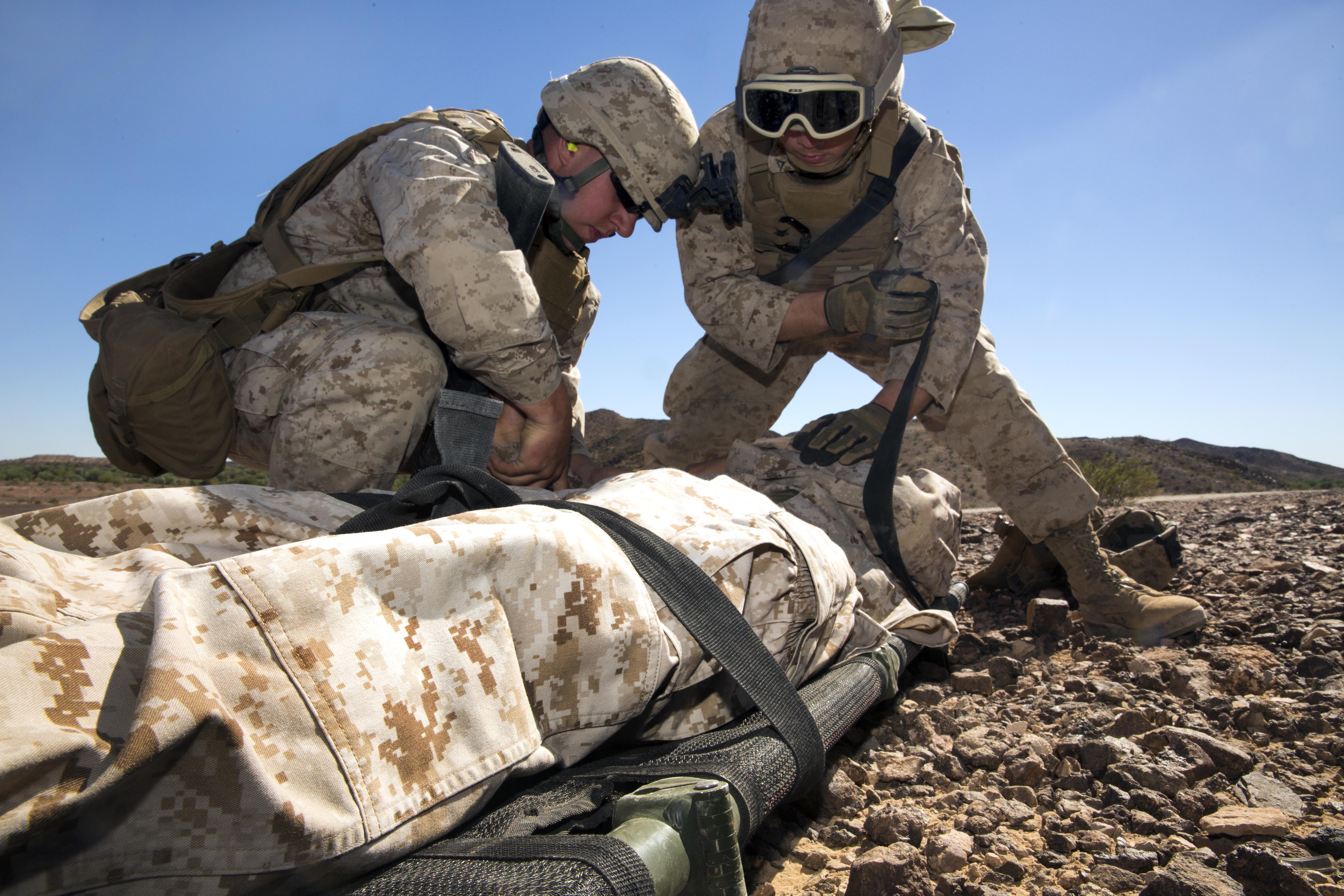 Marines strap a simulated casualty into a stretcher as part of their ...