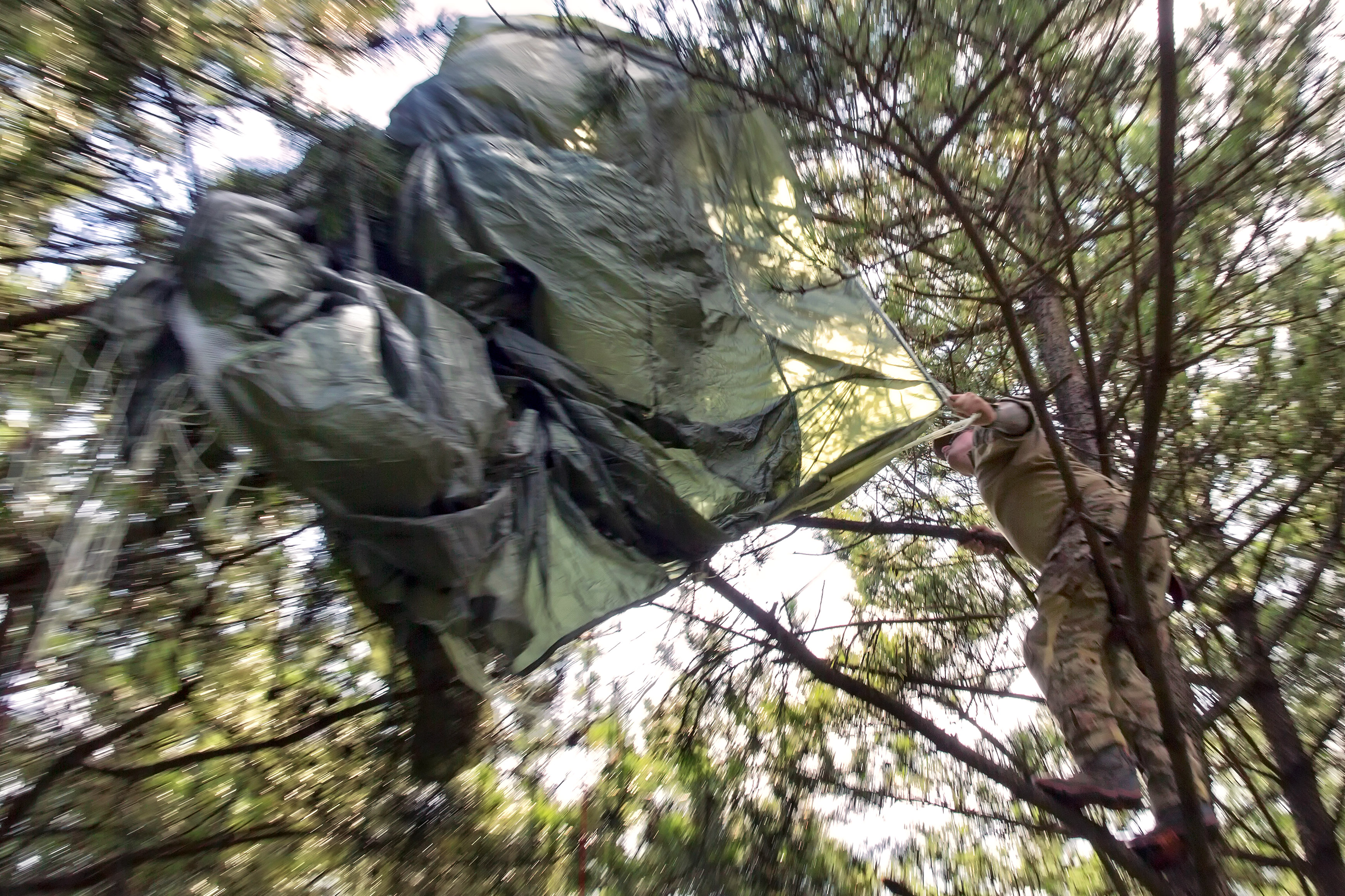 A U.S. soldier pulls a stuck parachute canopy from a tree after ...