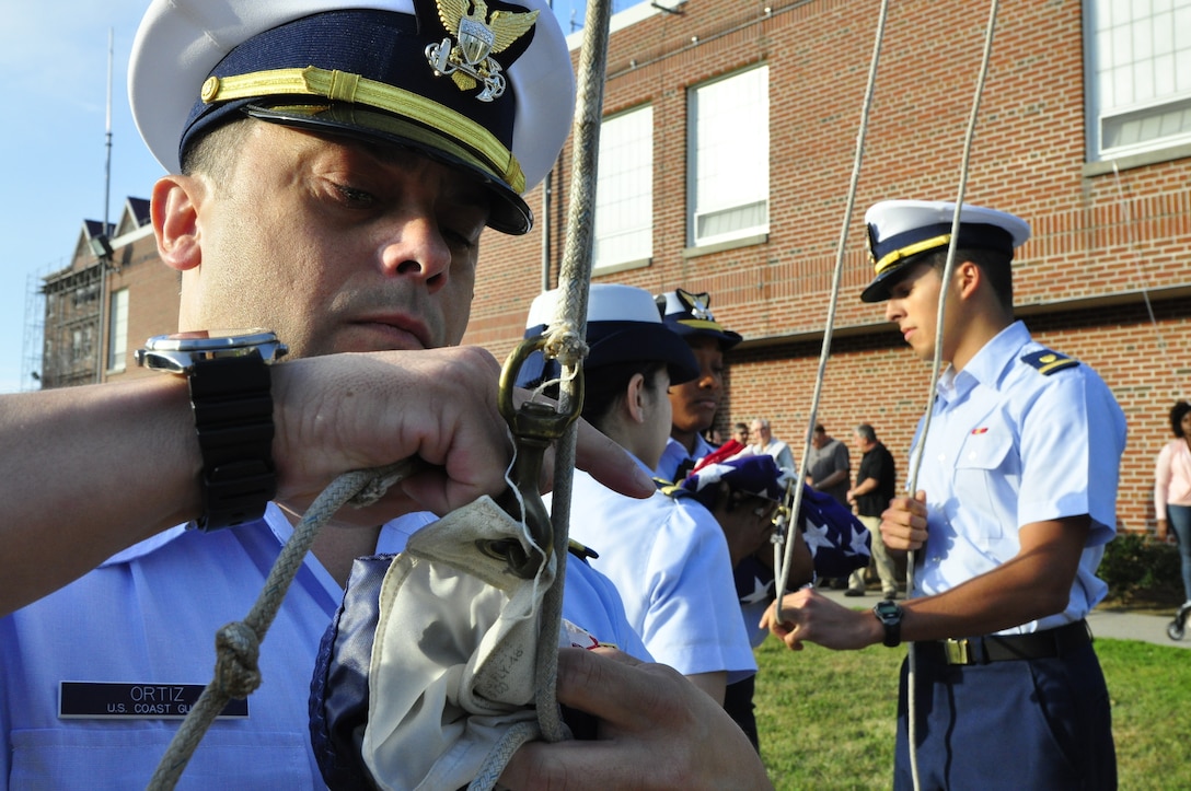 Coast Guard Ensign Michael Caballero prepares to hoist a flag during a ...