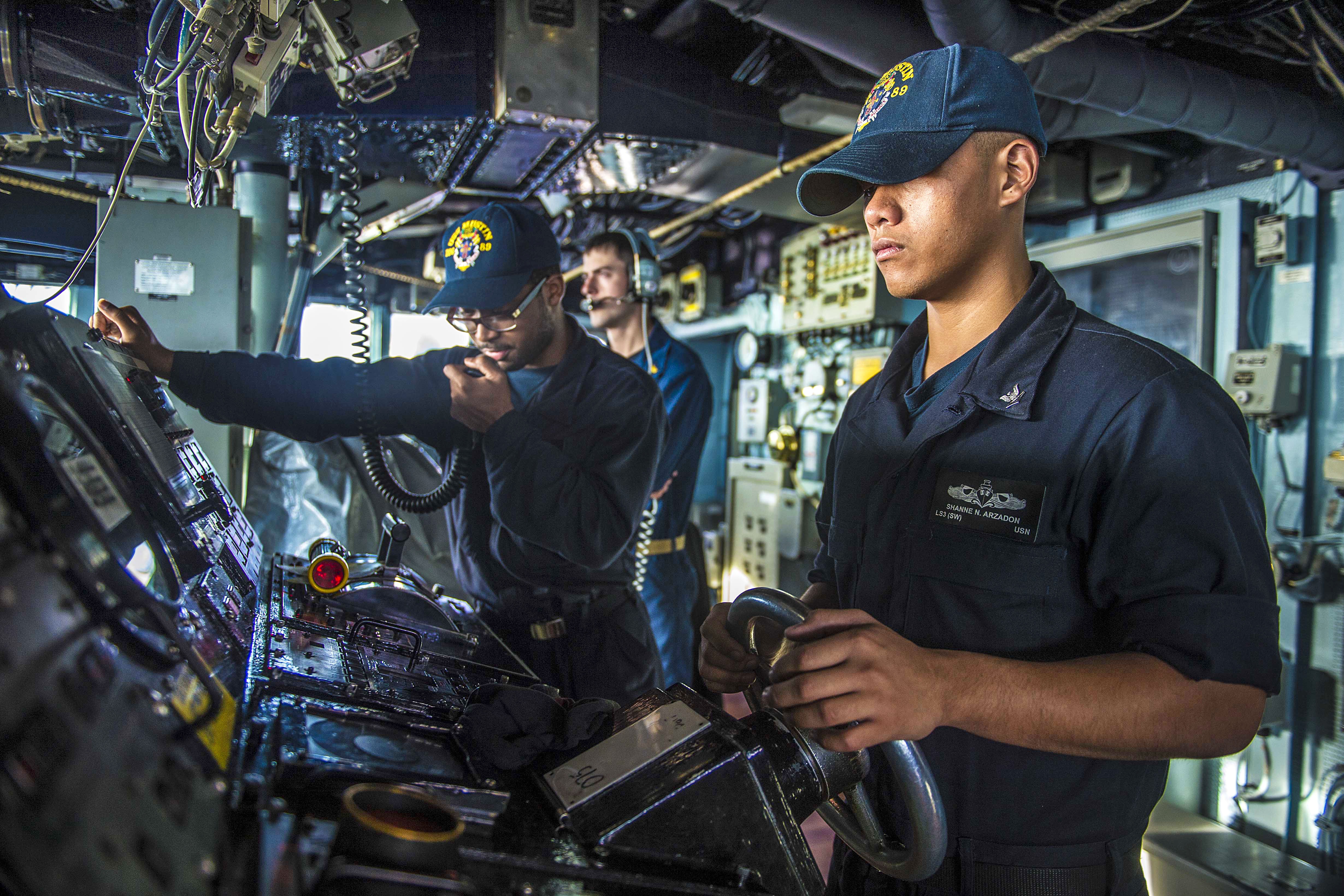 U.S. Navy Petty Officer 3rd Class Shanne Arzadon mans the helm in the ...