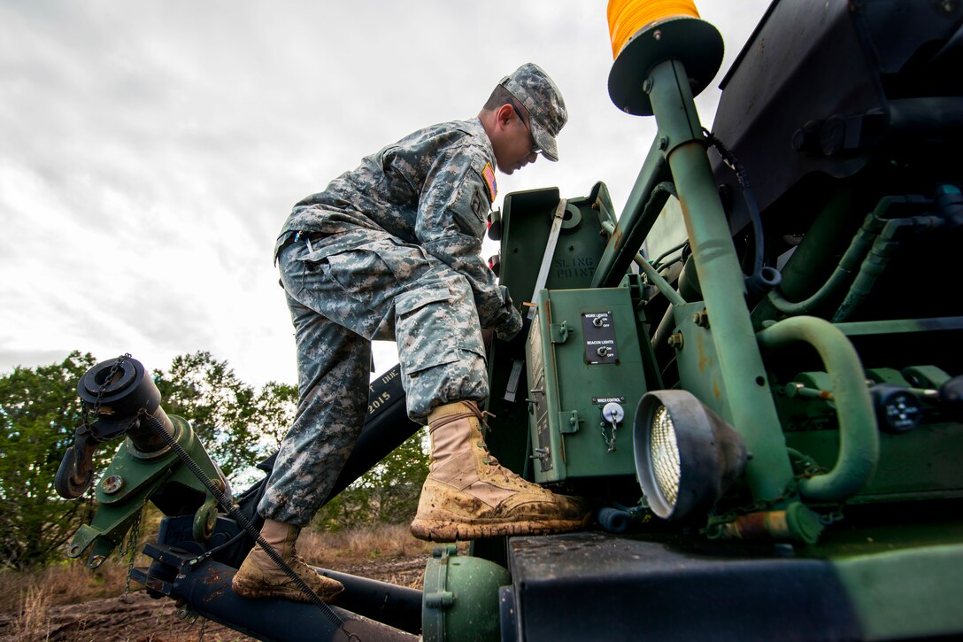 A soldier prepares the sling to recover a M984 wrecker truck stuck in ...