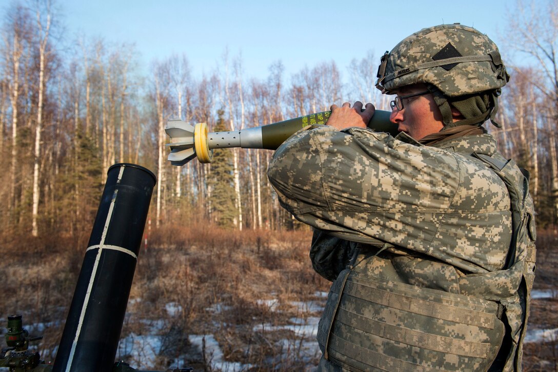 Army Pvt. Corey Peters loads a live round into an M121 120-mm mortar ...