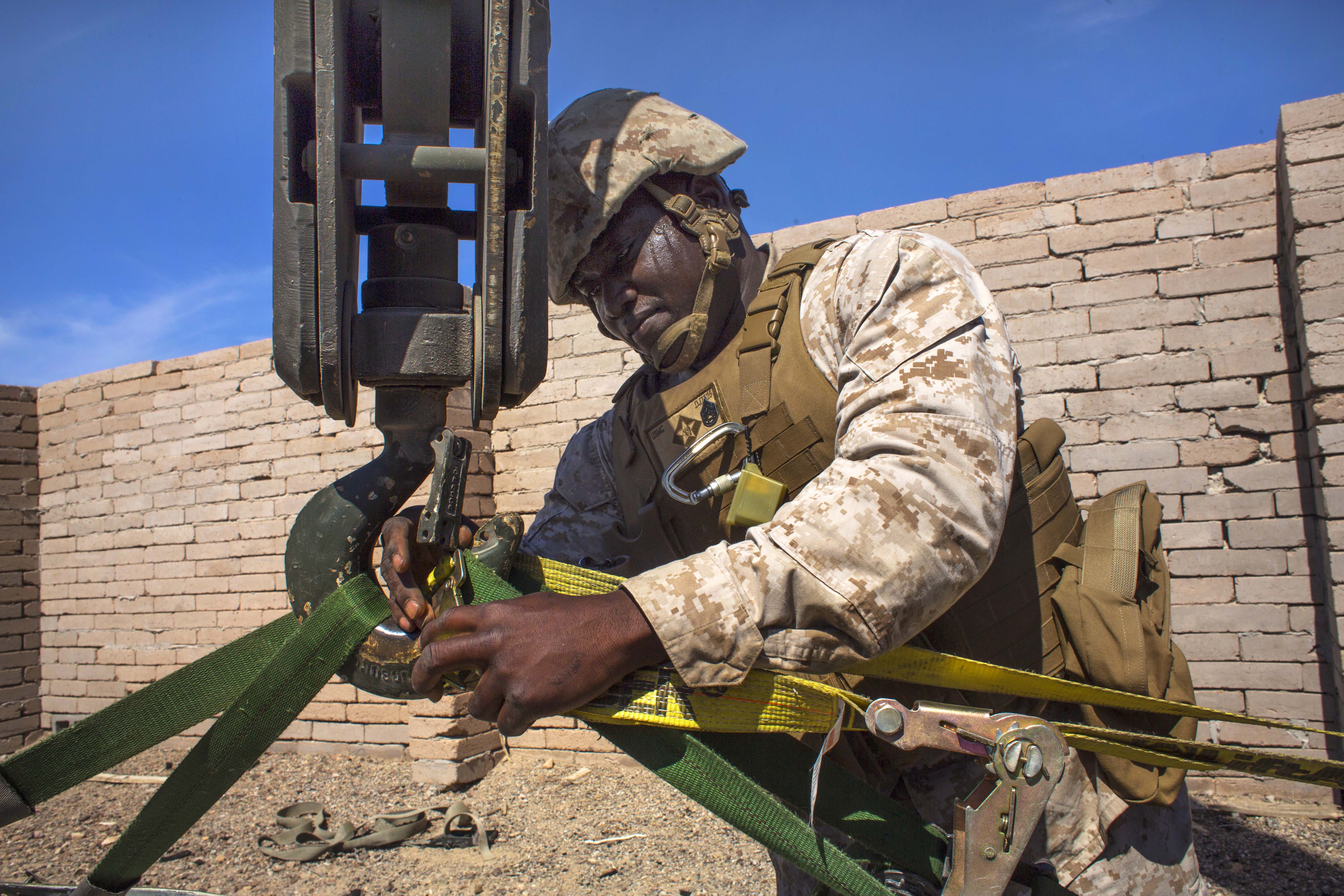 Marine Corps Staff Sgt. David E. Jefferson secures straps to a crane during aircraft salvage ...