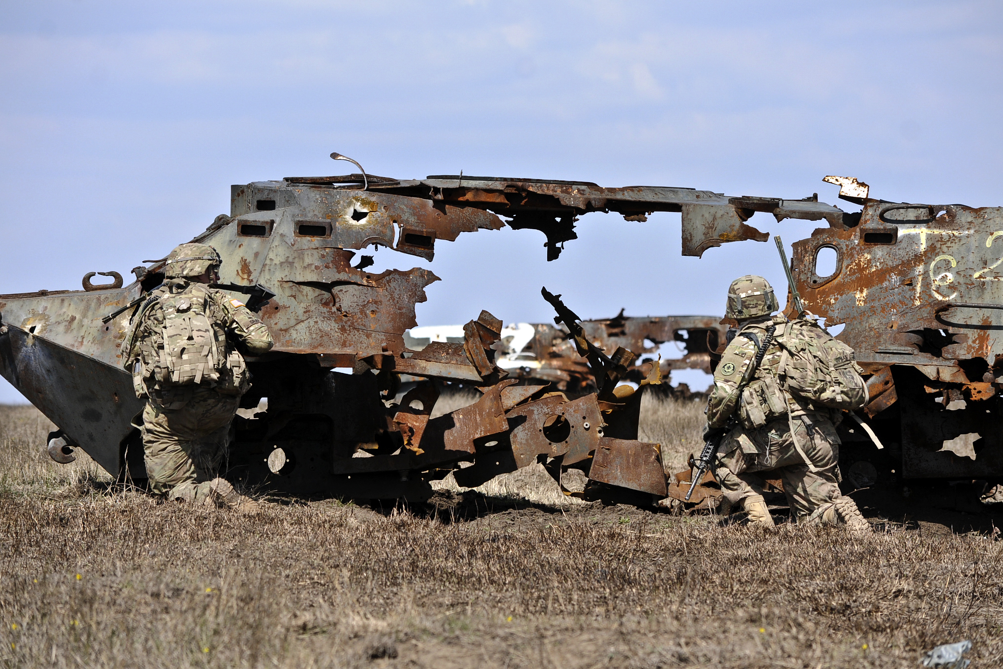 U.S. soldiers take cover behind an old military vehicle before moving ...