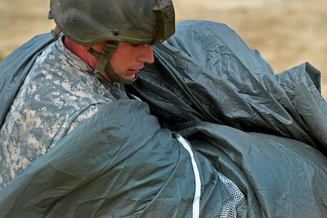 U.S. Army 1st Lt. Brinton Harrison begins to pack up his parachute ...
