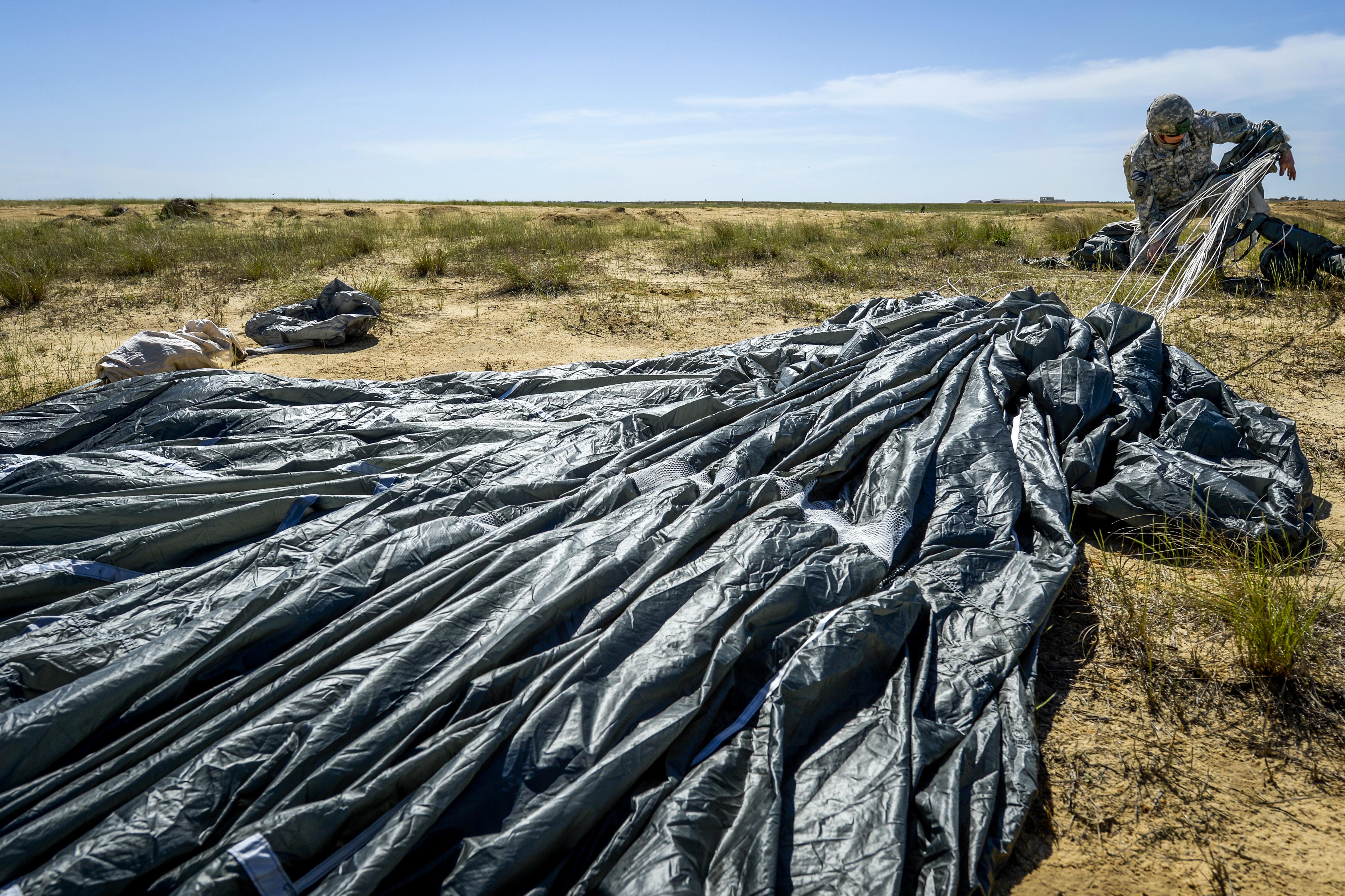 U.S. Army Staff Sgt. Jason Womack packs his parachute after completing ...