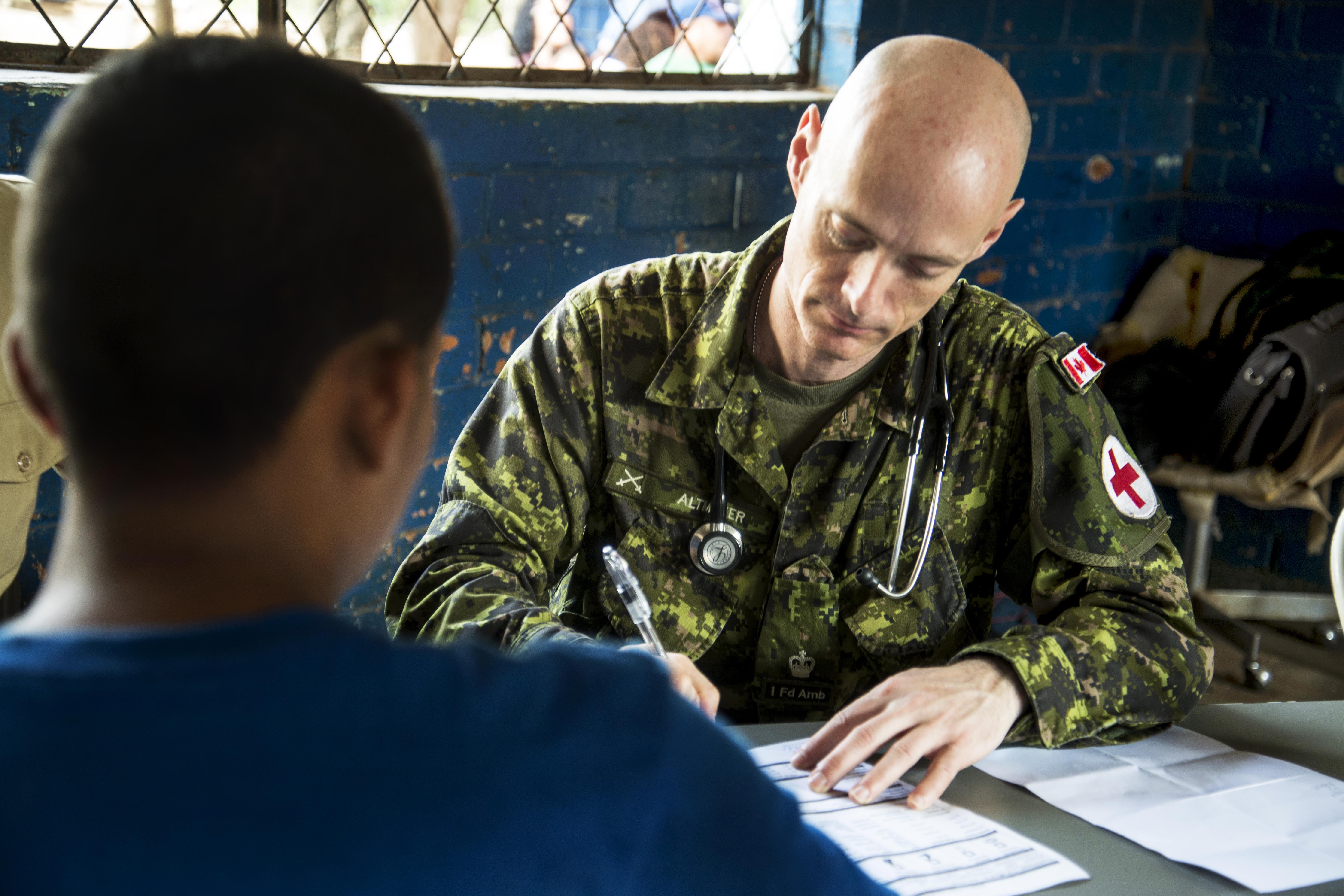 Canadian army Maj. Chris Altmeyer writes a prescription for a patient ...