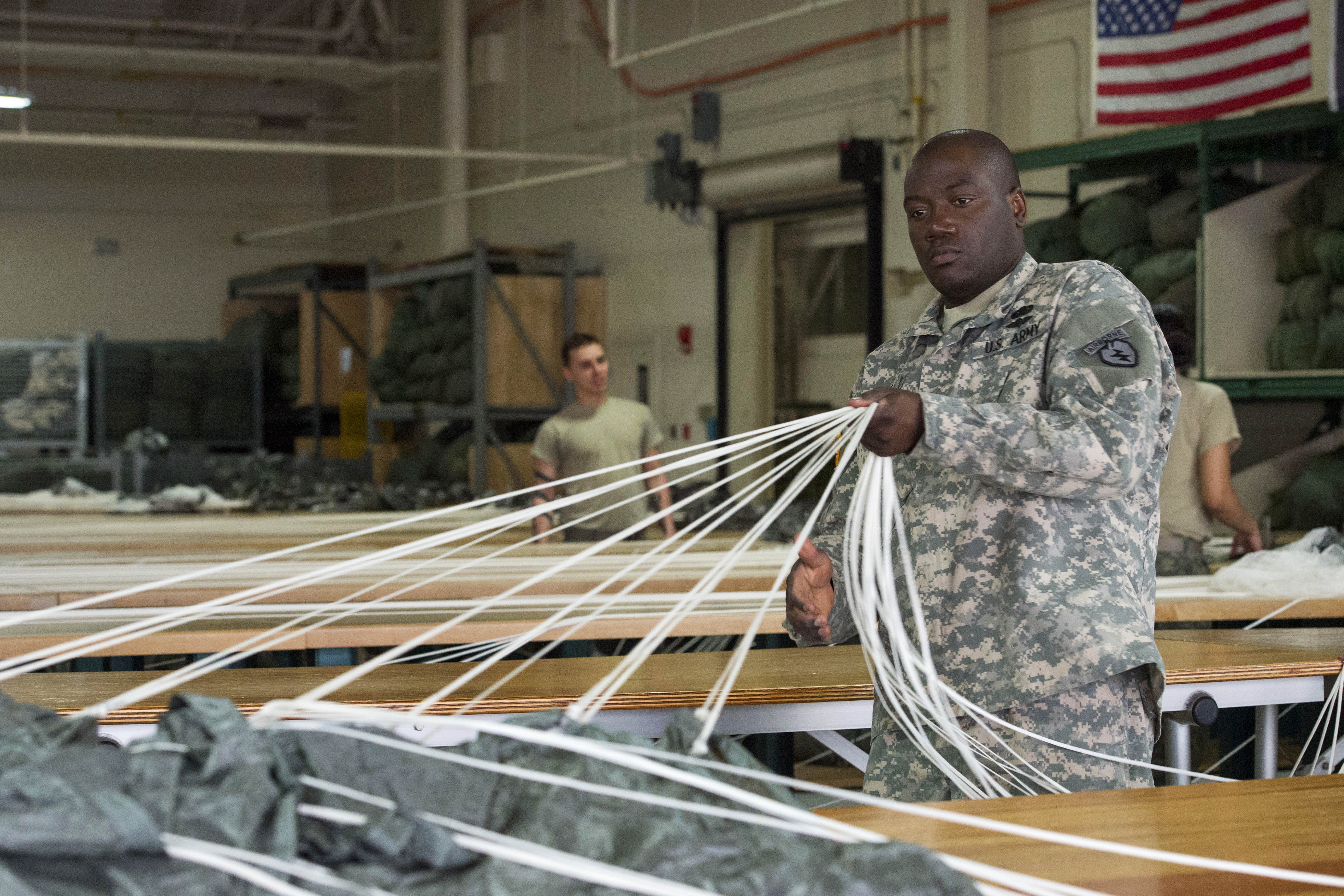 Army Spc. Kean Dennis arranges canopy cords while packing a T-11 ...