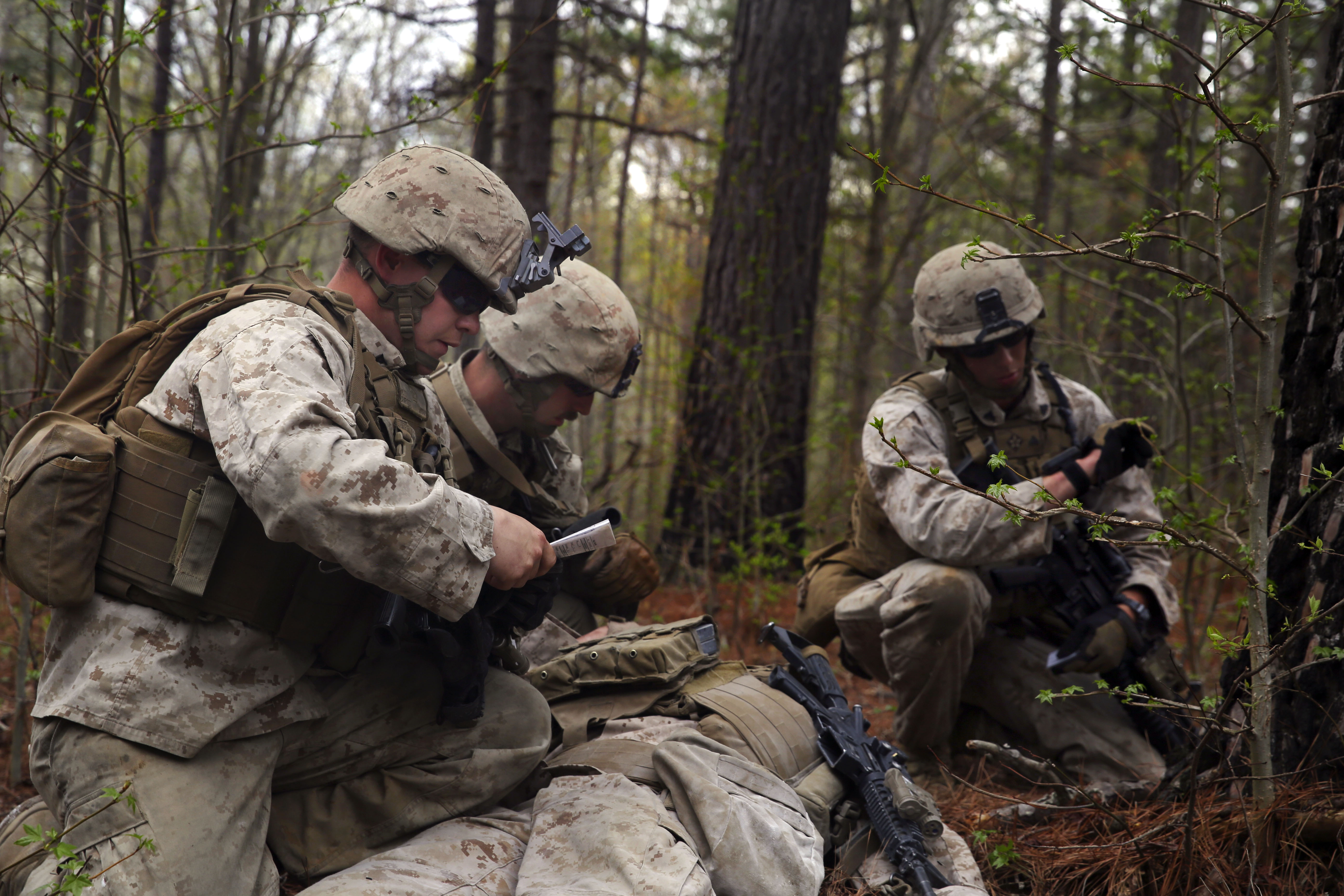 Marines provide medical aid to a comrade simulating injuries from an ...