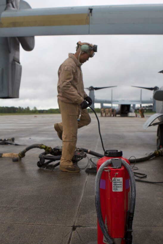 A U.S. Marine attaches a fuel pump module to an MV-22B Osprey as part ...