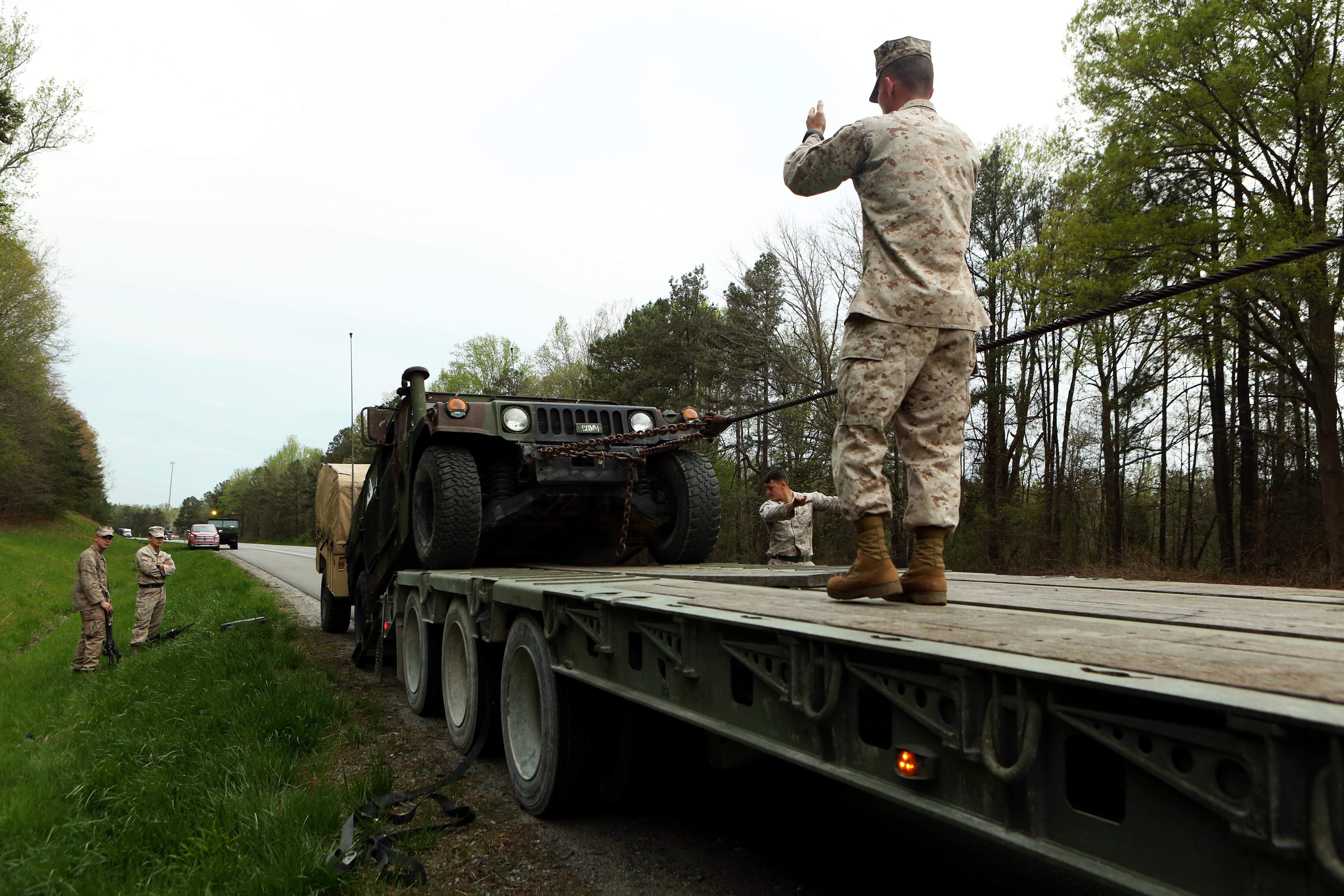 Marine Corps Staff Sgt. Michael Moore, right, ground guides a Humvee ...