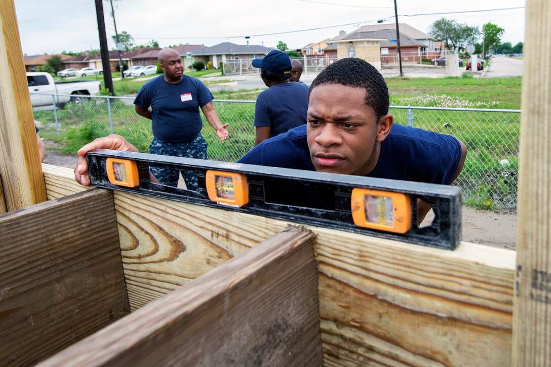 U.S. Navy Petty Officer 2nd Class Akili Johnson checks a side porch ...