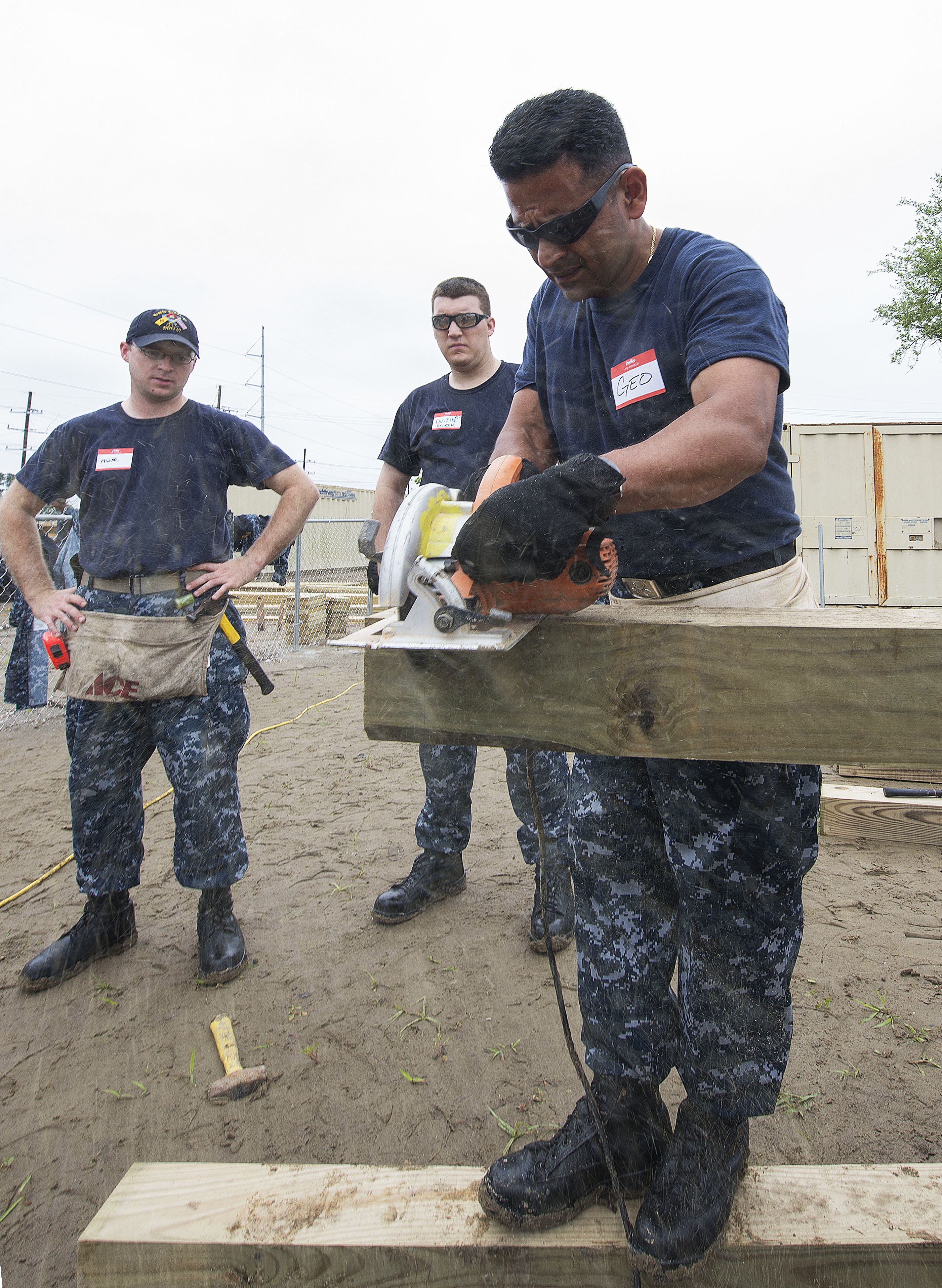 U.S. Navy Petty Officer 1st Class Geovanni Flores cuts a wood beam at a ...