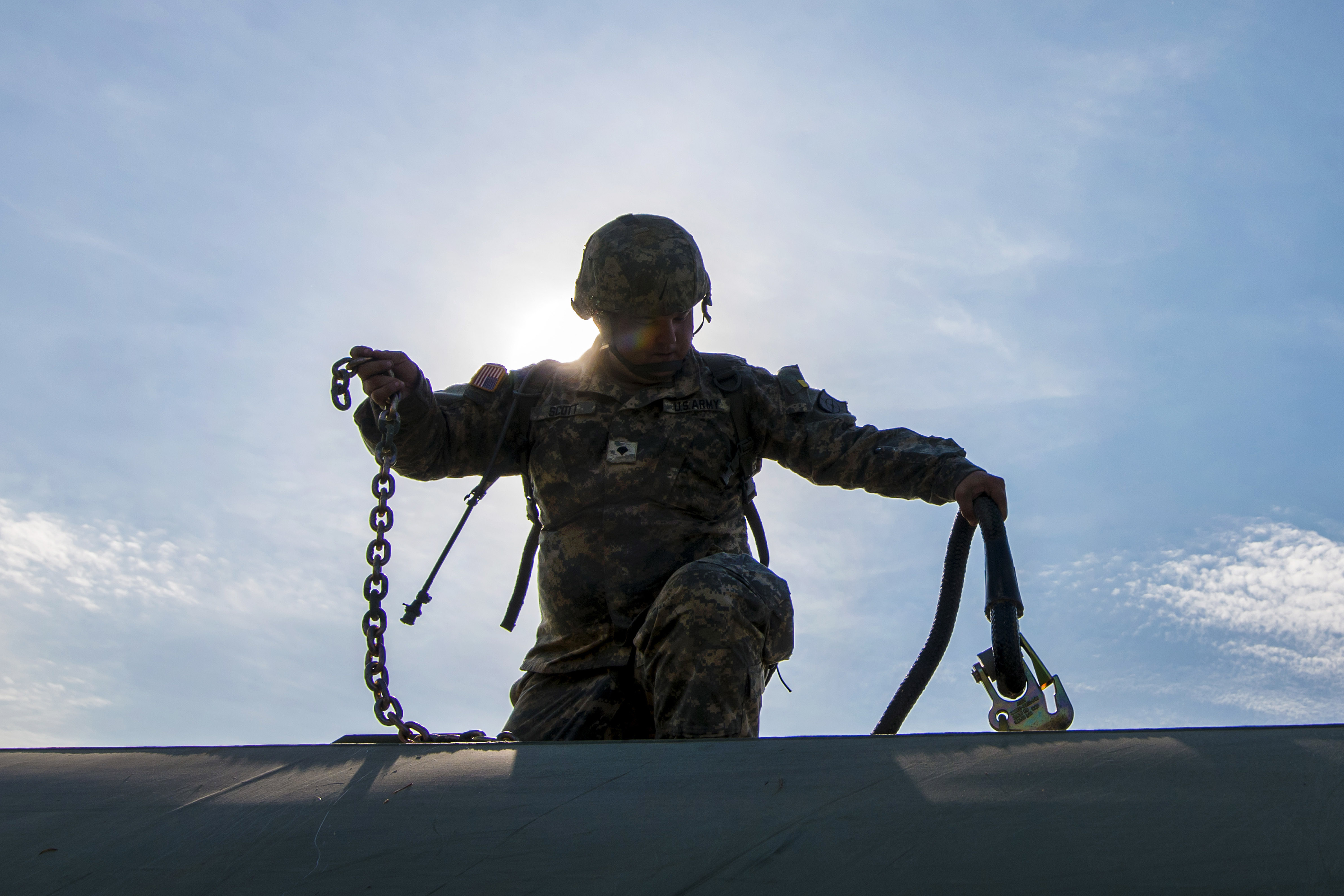 A soldier prepares to attach a chain and harness to a bridge bay during ...