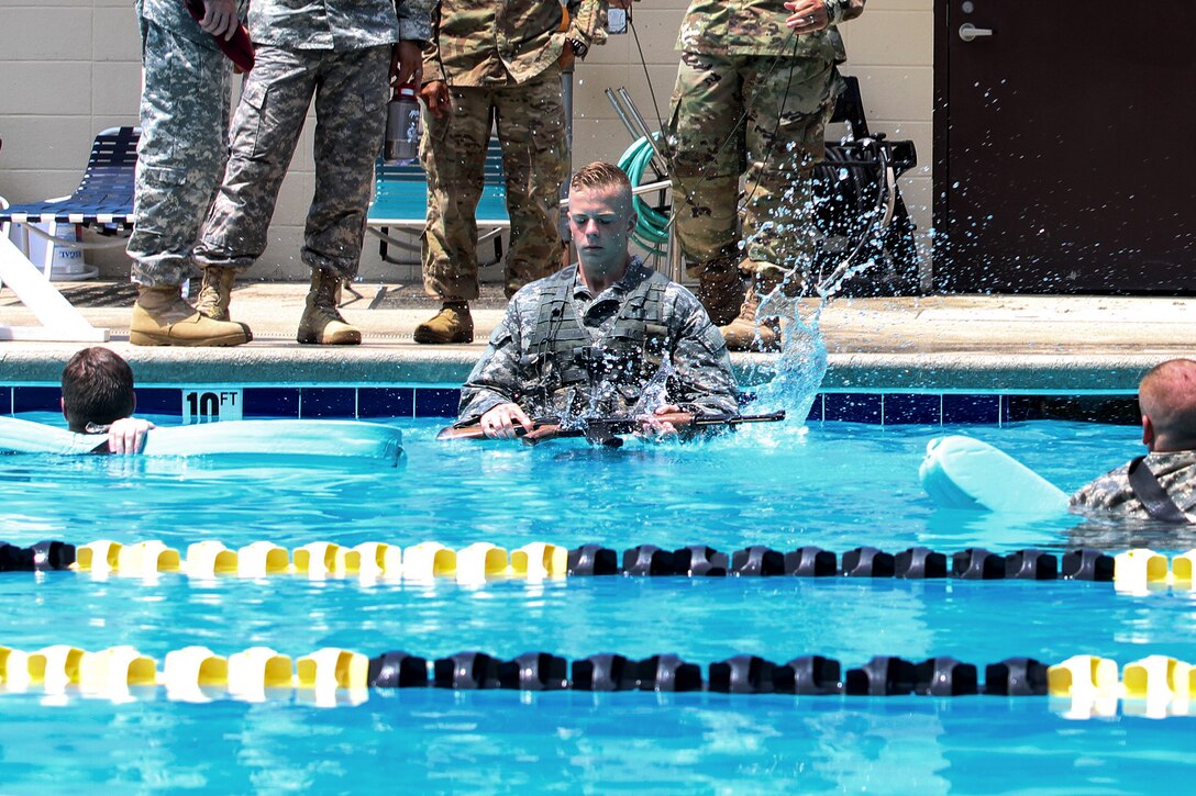 A paratrooper jumps into a swimming pool during combat water survival ...