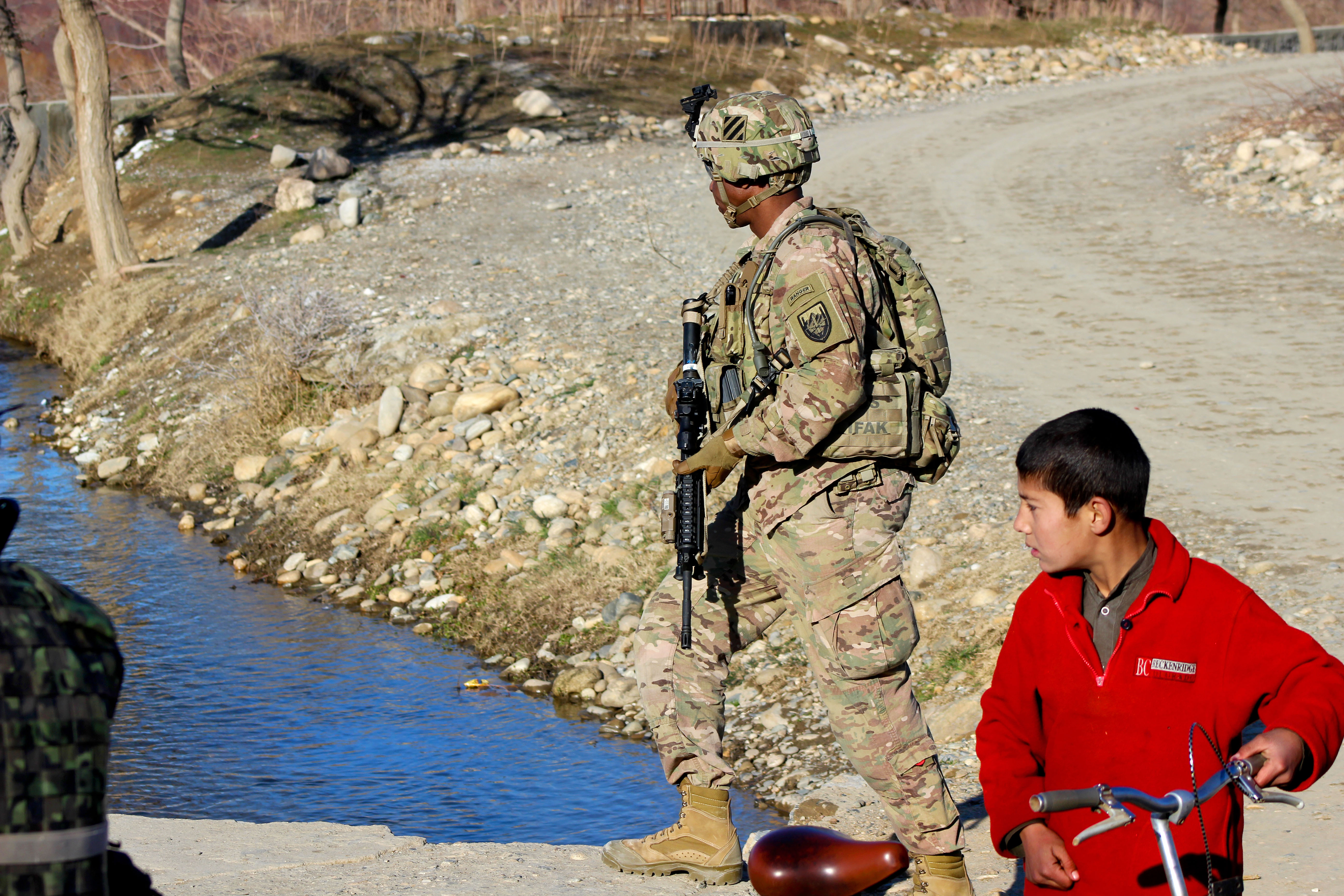 U.S. Army Command Sgt. Major Christopher Gilpin crosses a small stream ...