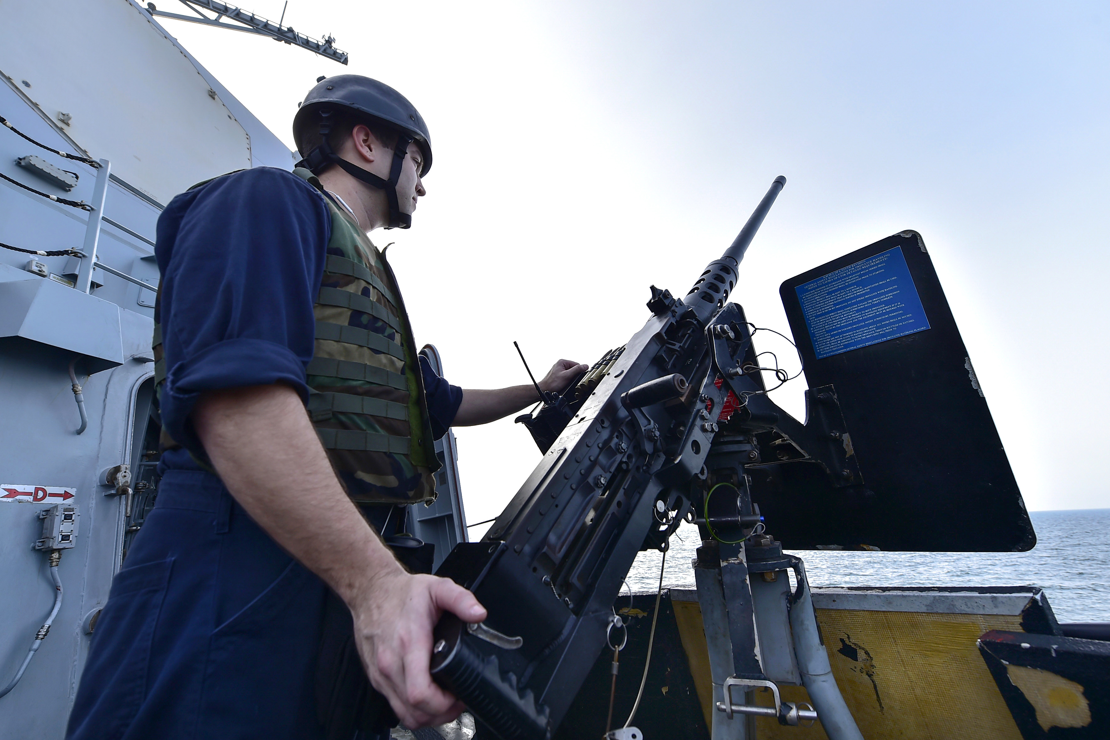 U.S. Navy Petty Officer 2nd Class Andrew Thayer mans an M2HB .50 ...