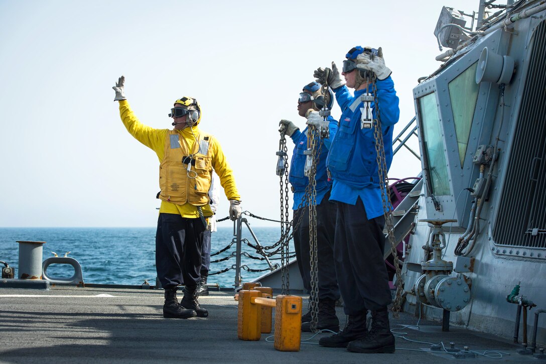 U.S. Navy Petty Officer 2nd Class John Acheson signals to pilots that ...