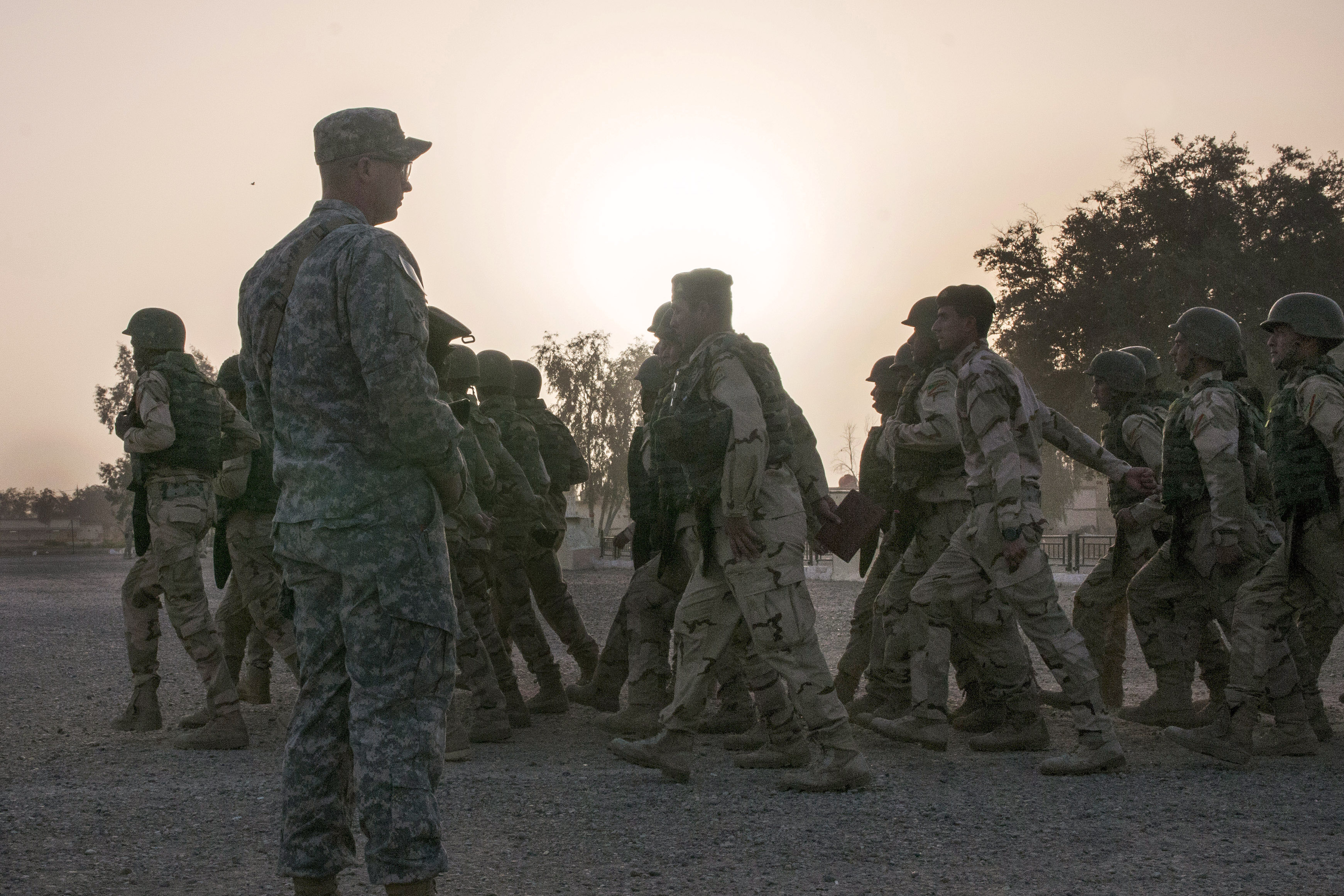A U.S. Soldier watches as Iraqi army soldiers march on Camp Taji, Iraq ...