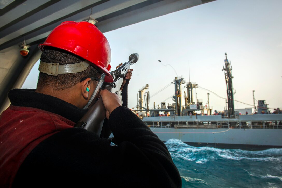 U.S. Navy Seaman Deaon Mahone fires a shot line from an M14 rifle on a ...