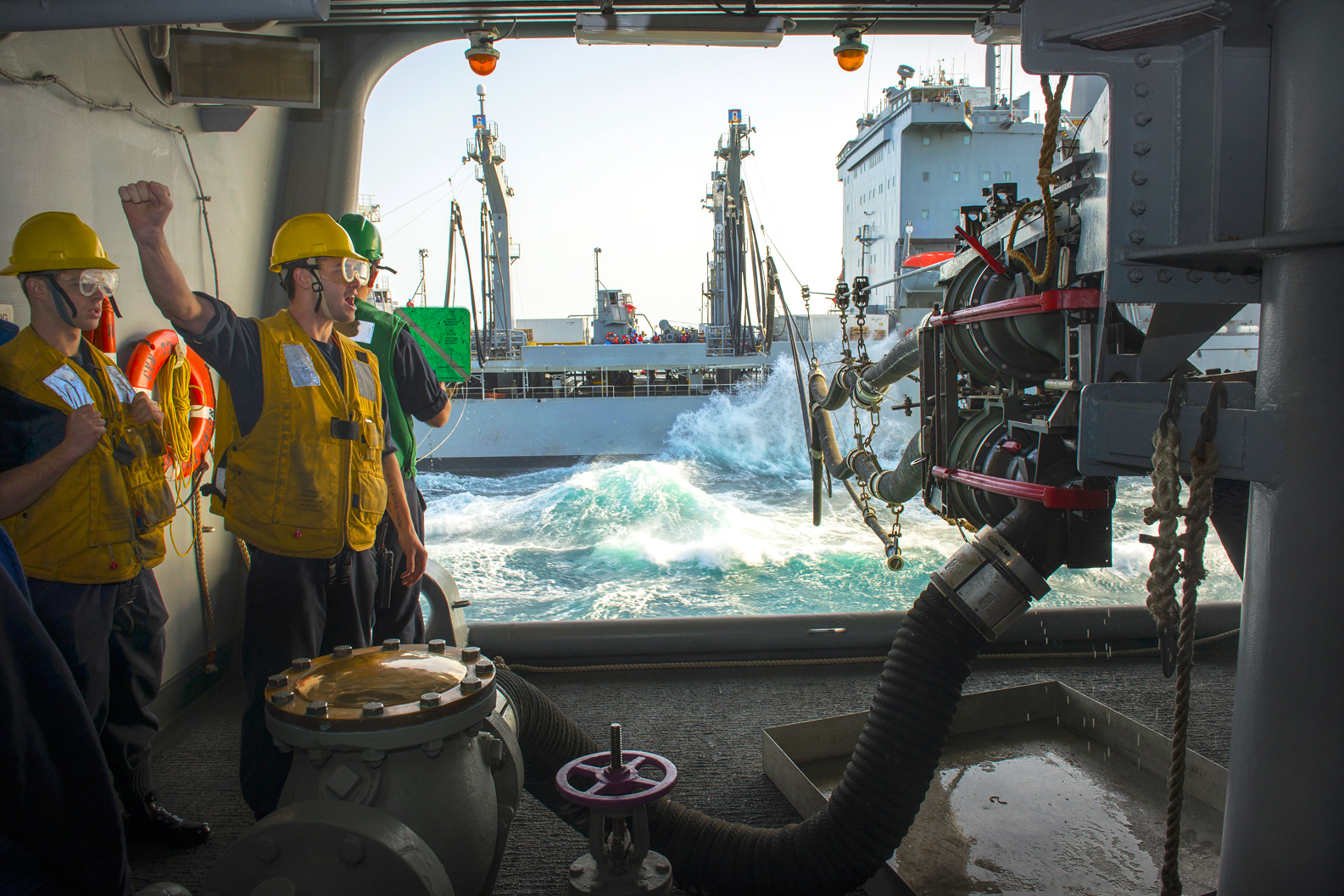 U.S. Navy Petty Officer 2nd Class Timmothy Annoni, right, signals fuel ...