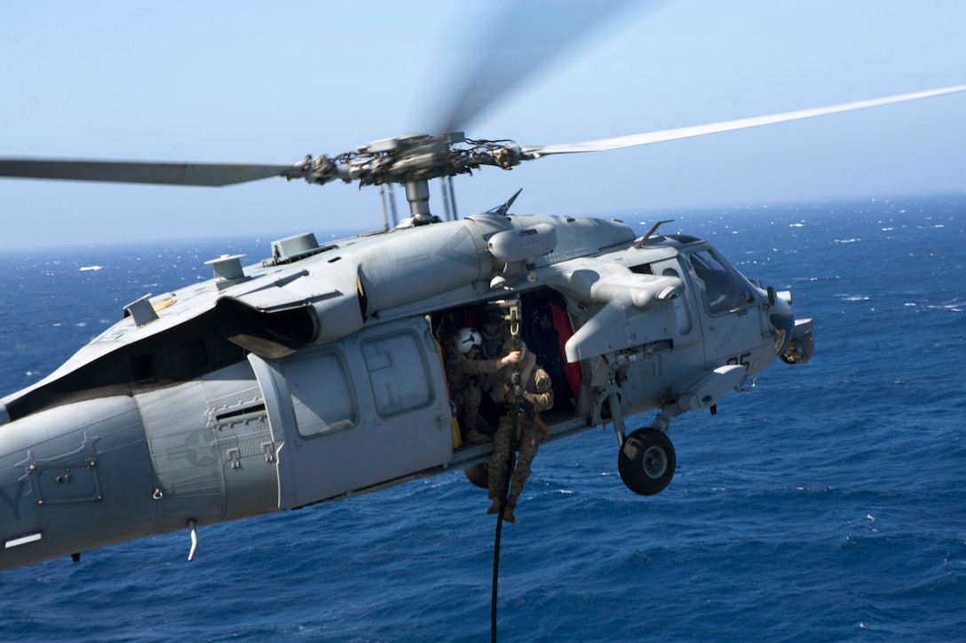 A U.S. Marine fast ropes out of an MH-60 Seahawk helicopter aboard the ...