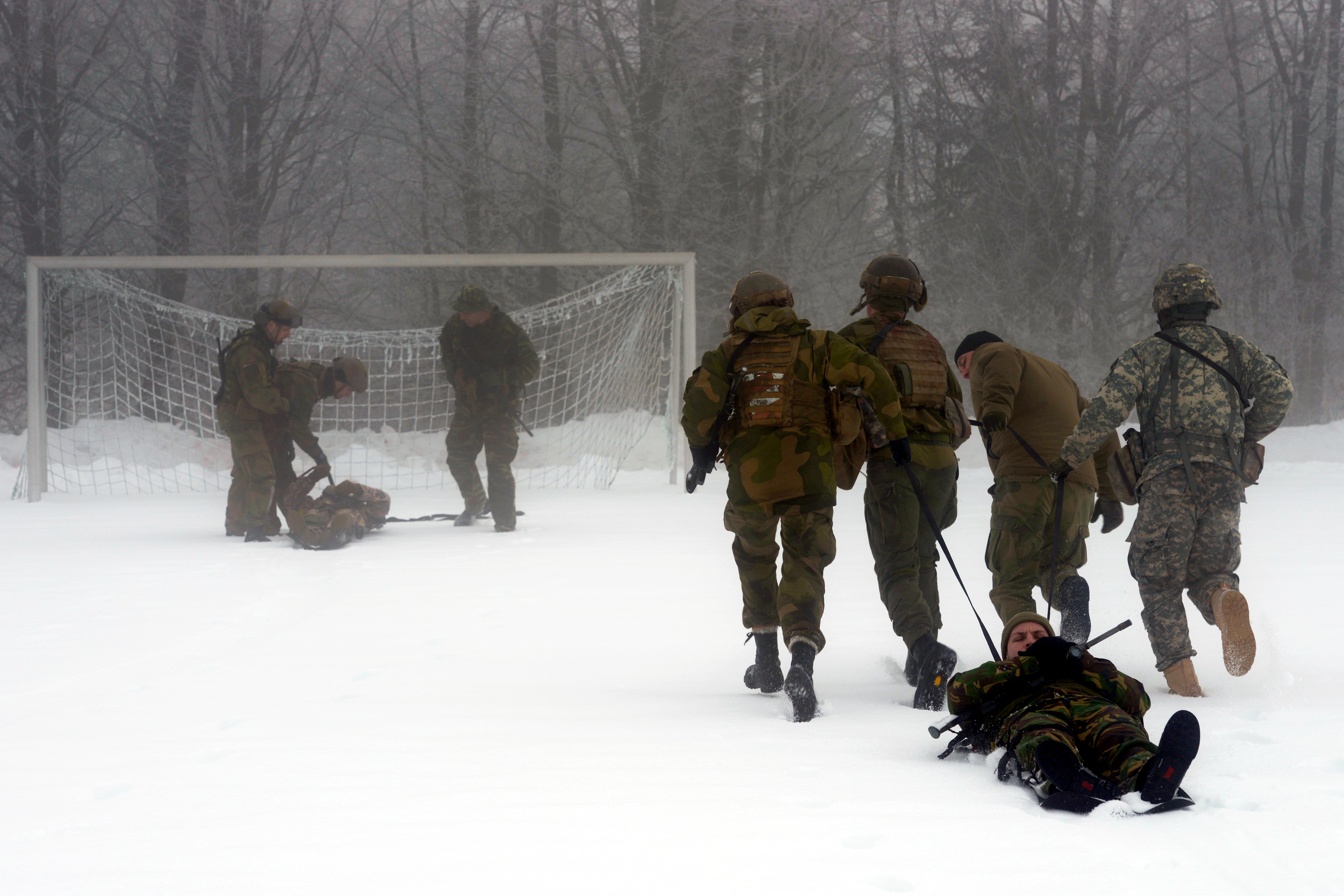 Soldiers drag a simulated casualty on an evacuation stretcher litter ...
