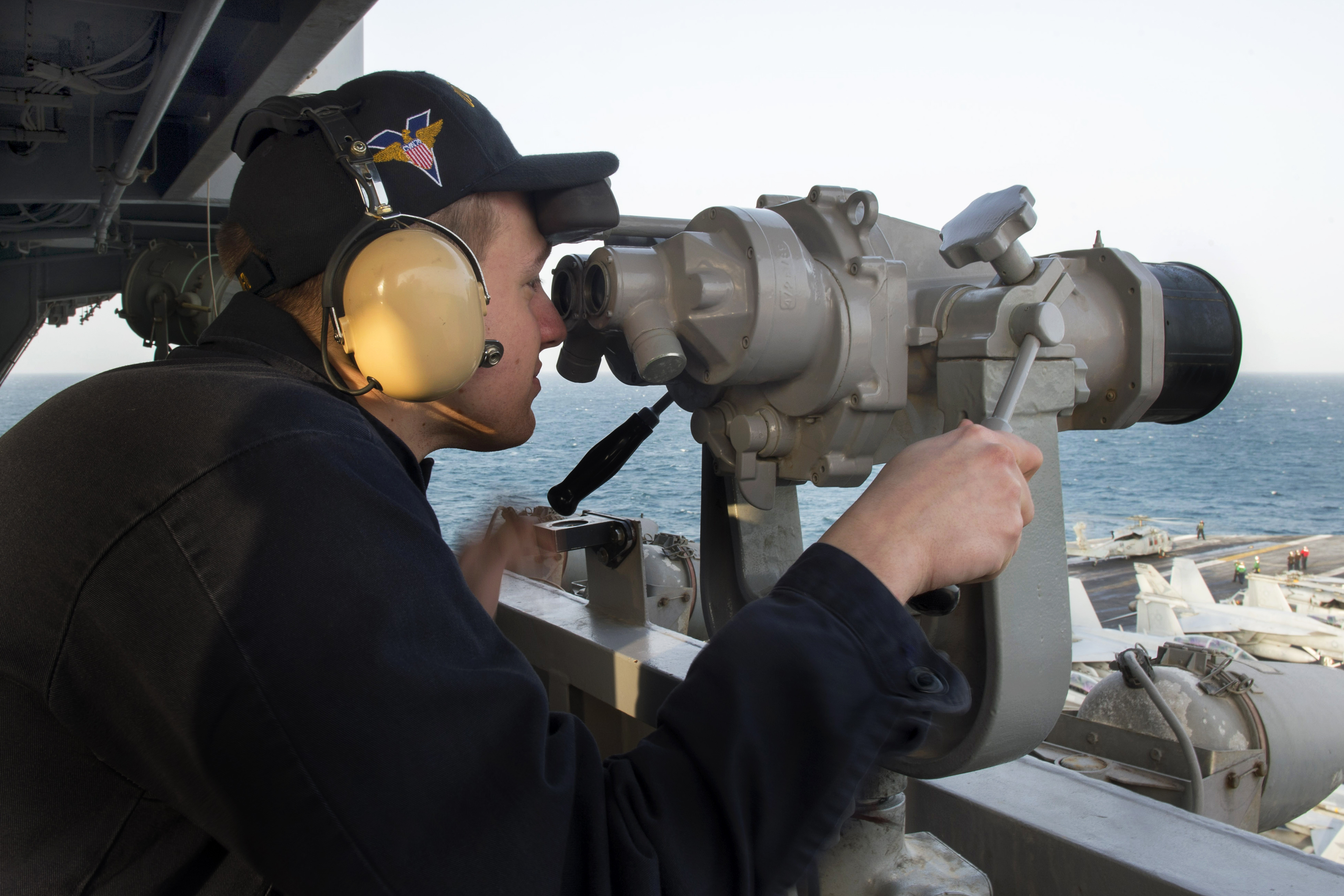 U.S. Navy Seaman Andrew Thompson uses high-powered binoculars to scan ...