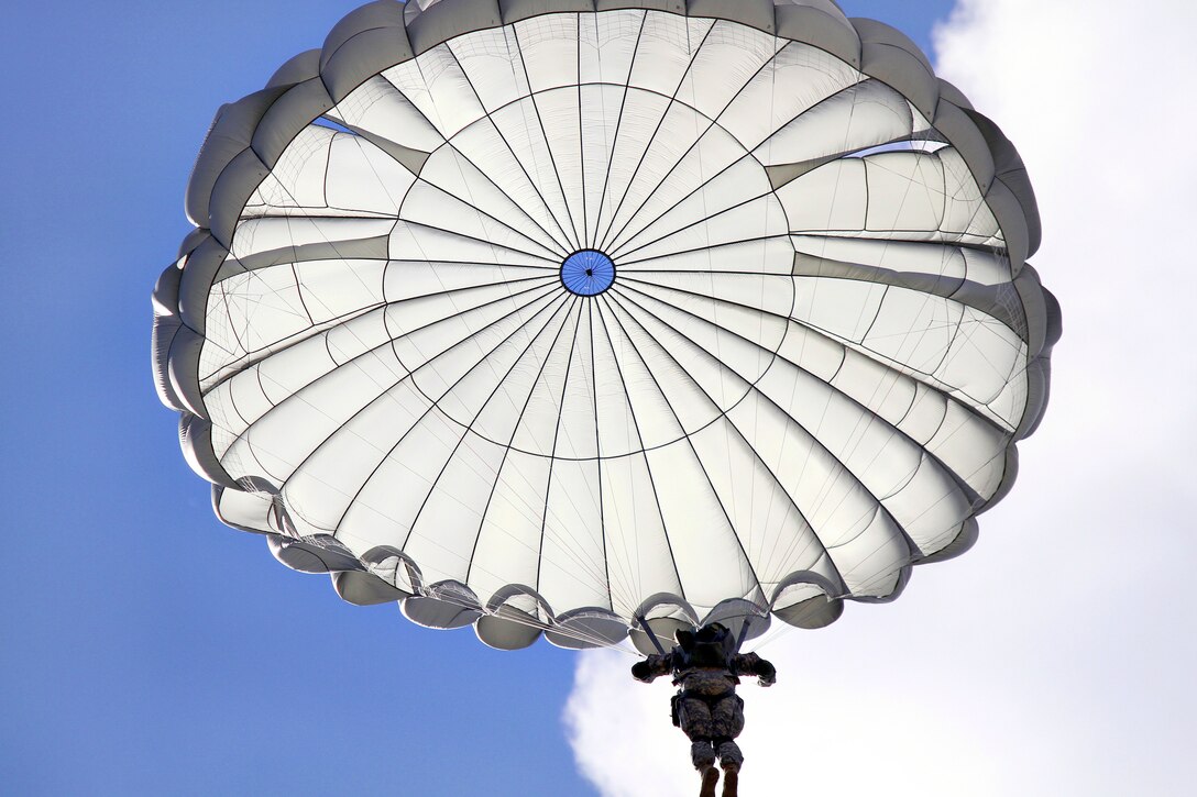 A paratrooper pulls the toggles on the MC-6 parachute to prepare to ...