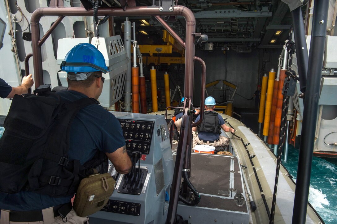 U.S. Navy Petty Officer 1st Class Tyler Horn maneuvers a rigid hull ...