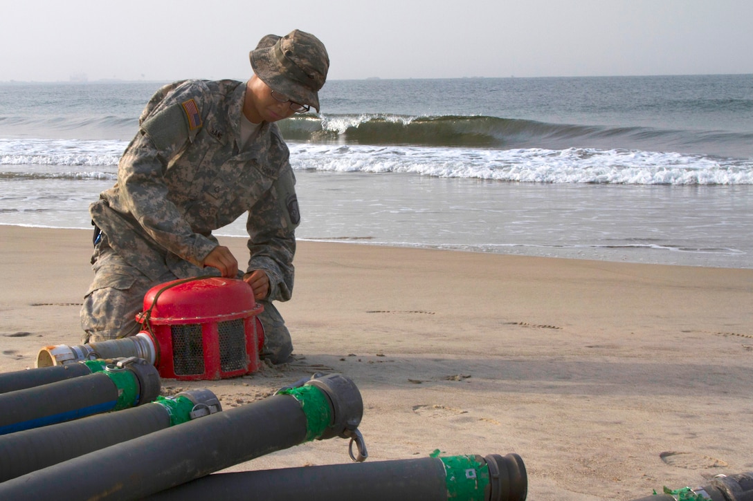 U.S. Army Pfc. Tieyu Zhang, foreground, prepares a pump to be put into ...