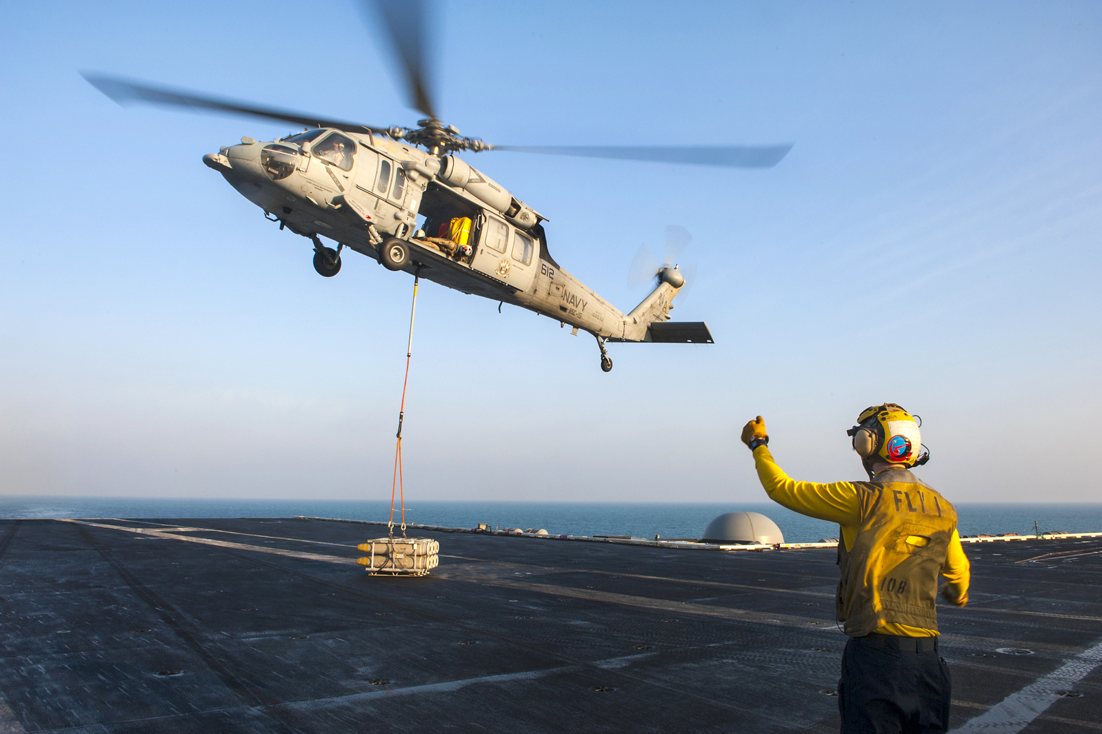 U.S. Navy Petty Officer 3rd Class Brandon Moser directs an MH-60S Sea ...